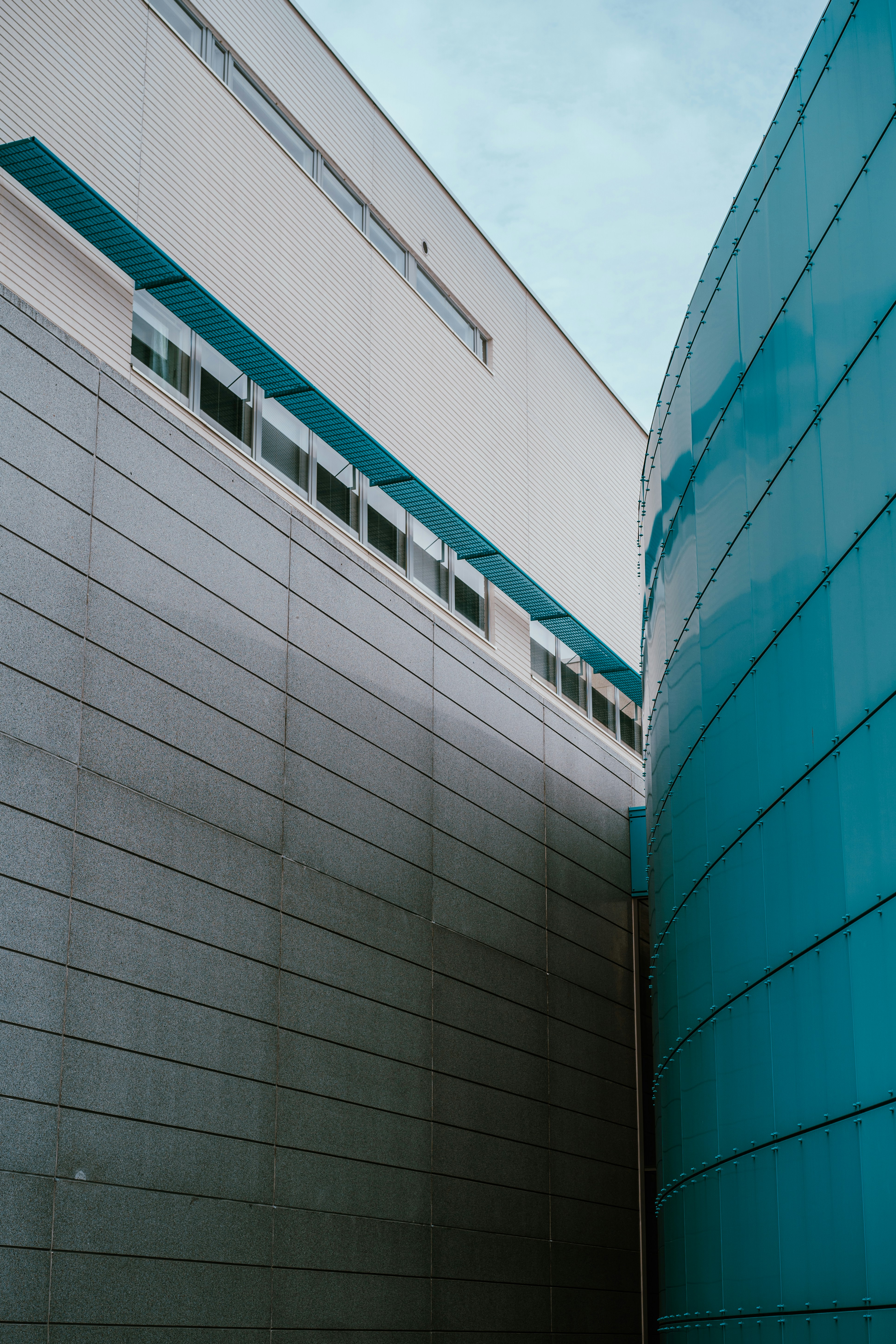 Abstract architectural composition featuring a blend of textured gray walls and a smooth, reflective blue cylinder.
