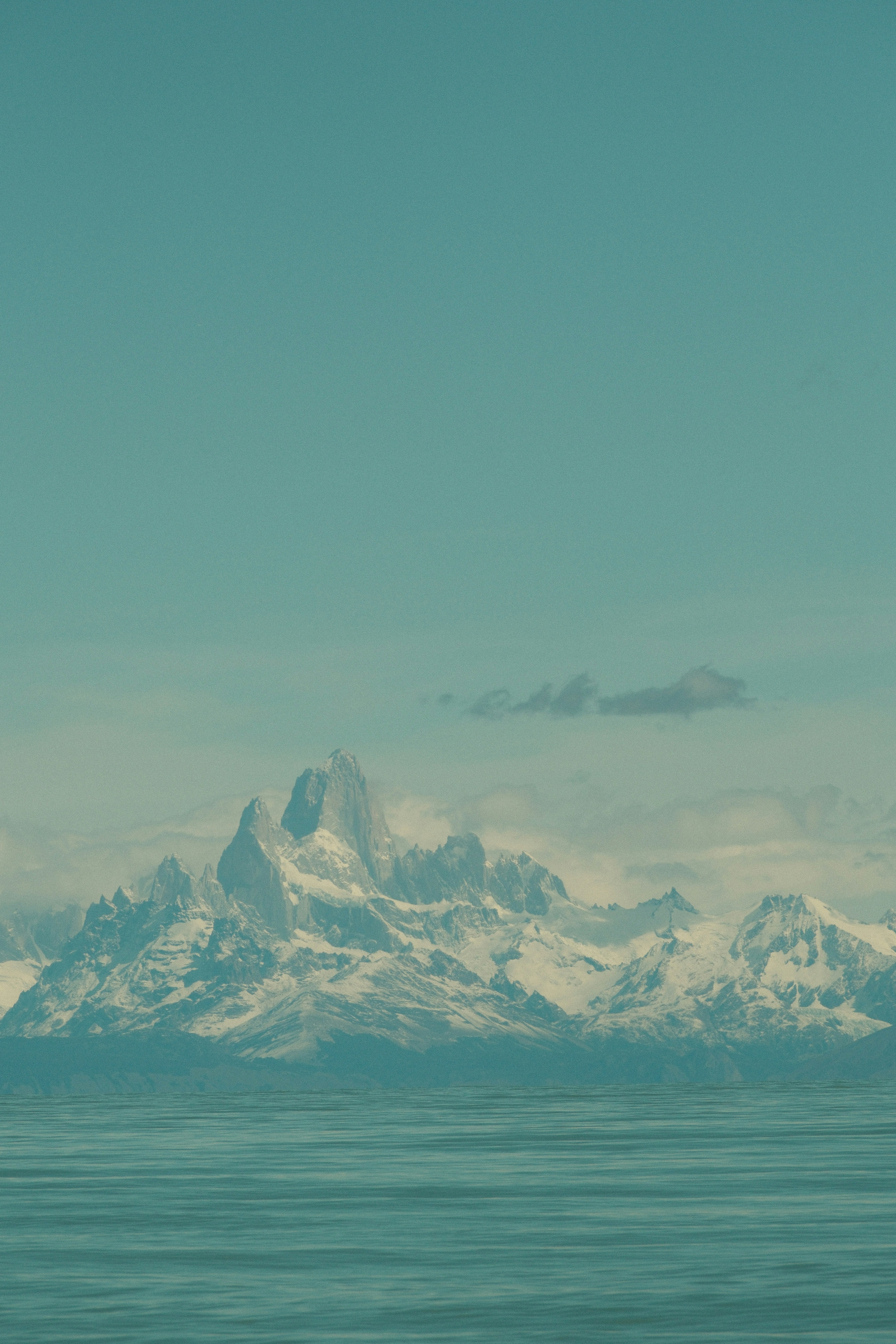 Teal Horizon: Snowbound Peaks Rising Over a Calm Sea