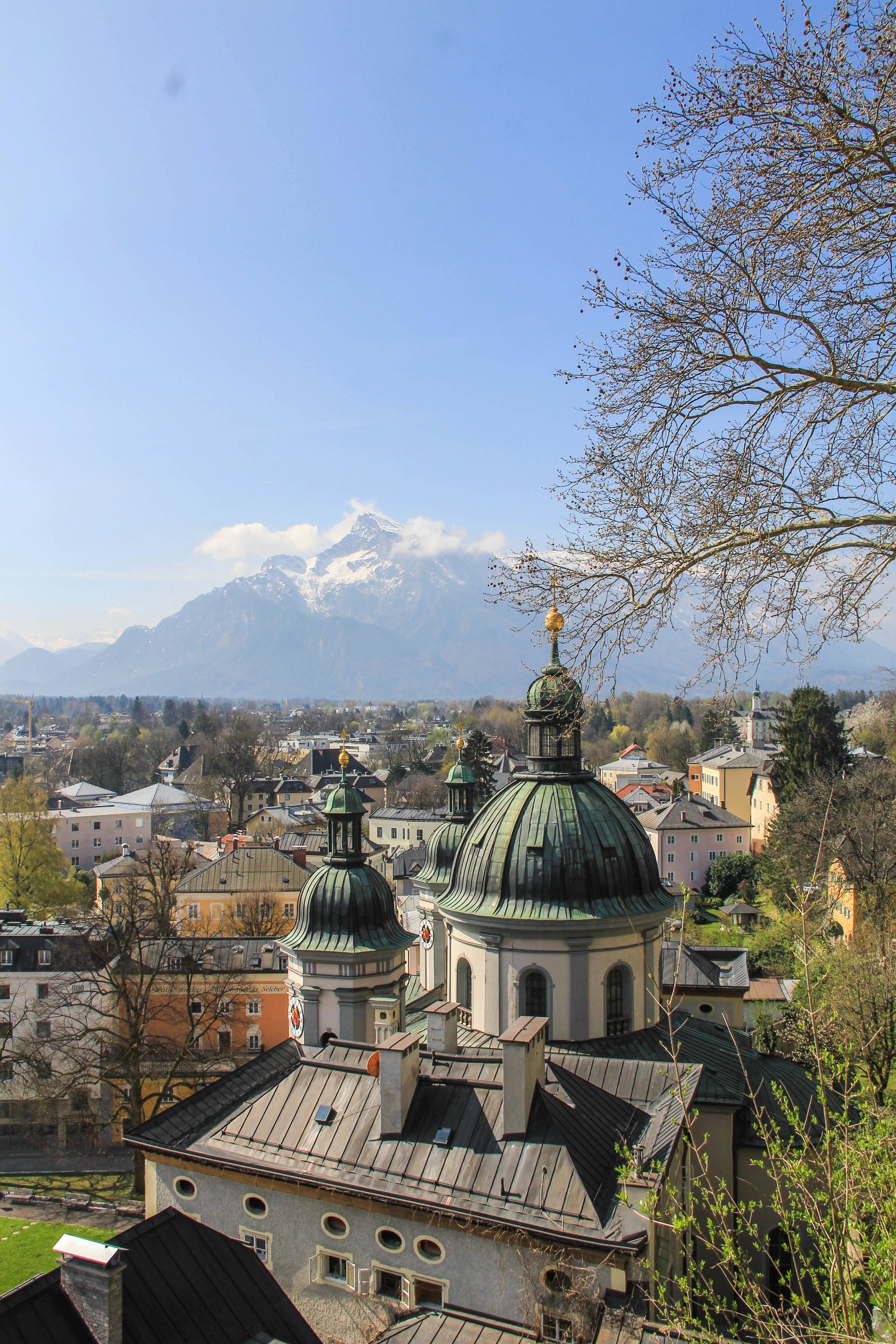 Salzburg, Austria | A church and mountains stand under a blue sky.