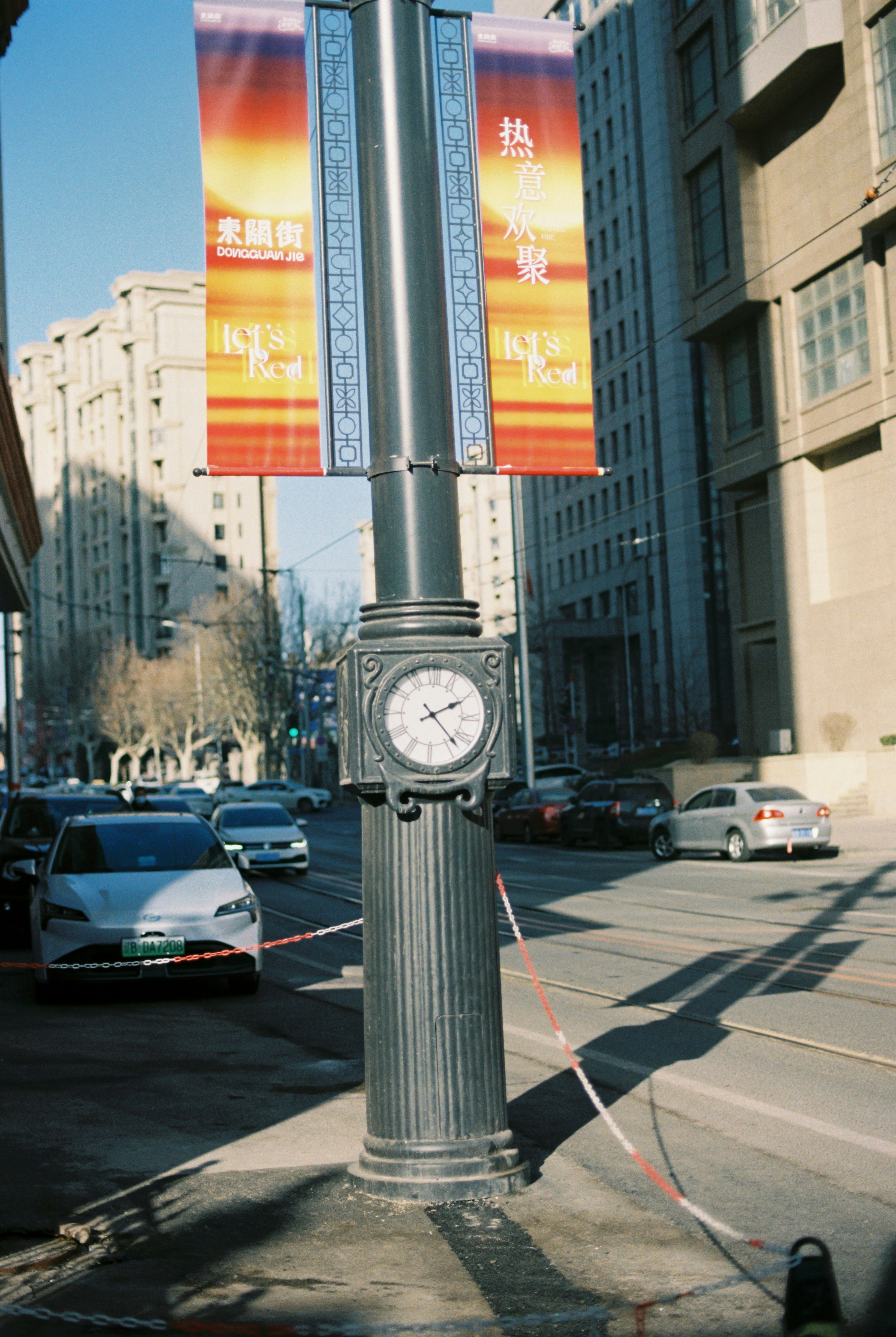 Timekeeper on a City Street: A Clock-Framed Moment Beneath Bannered Lampposts