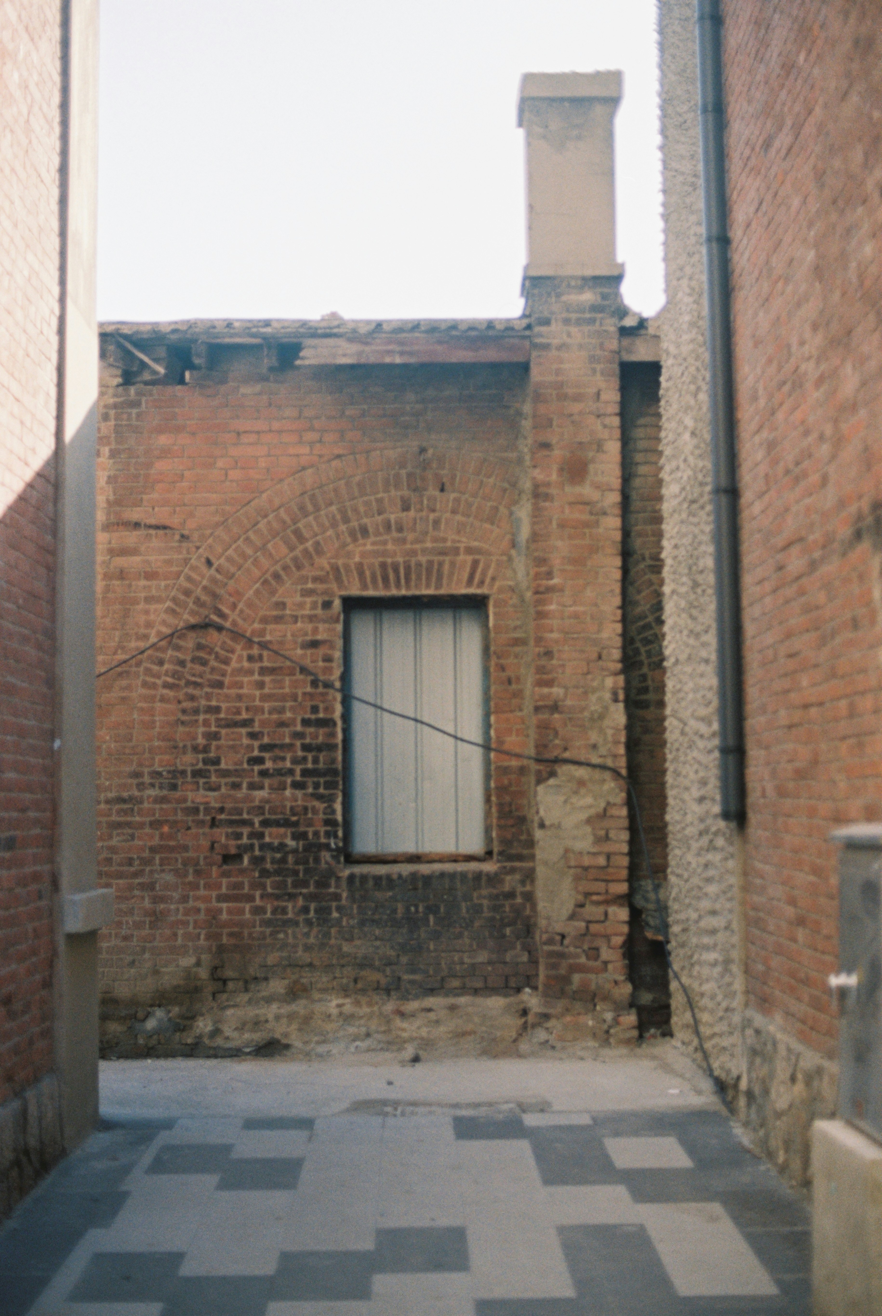 Arched Brick Window Anchored in a Quiet Alley