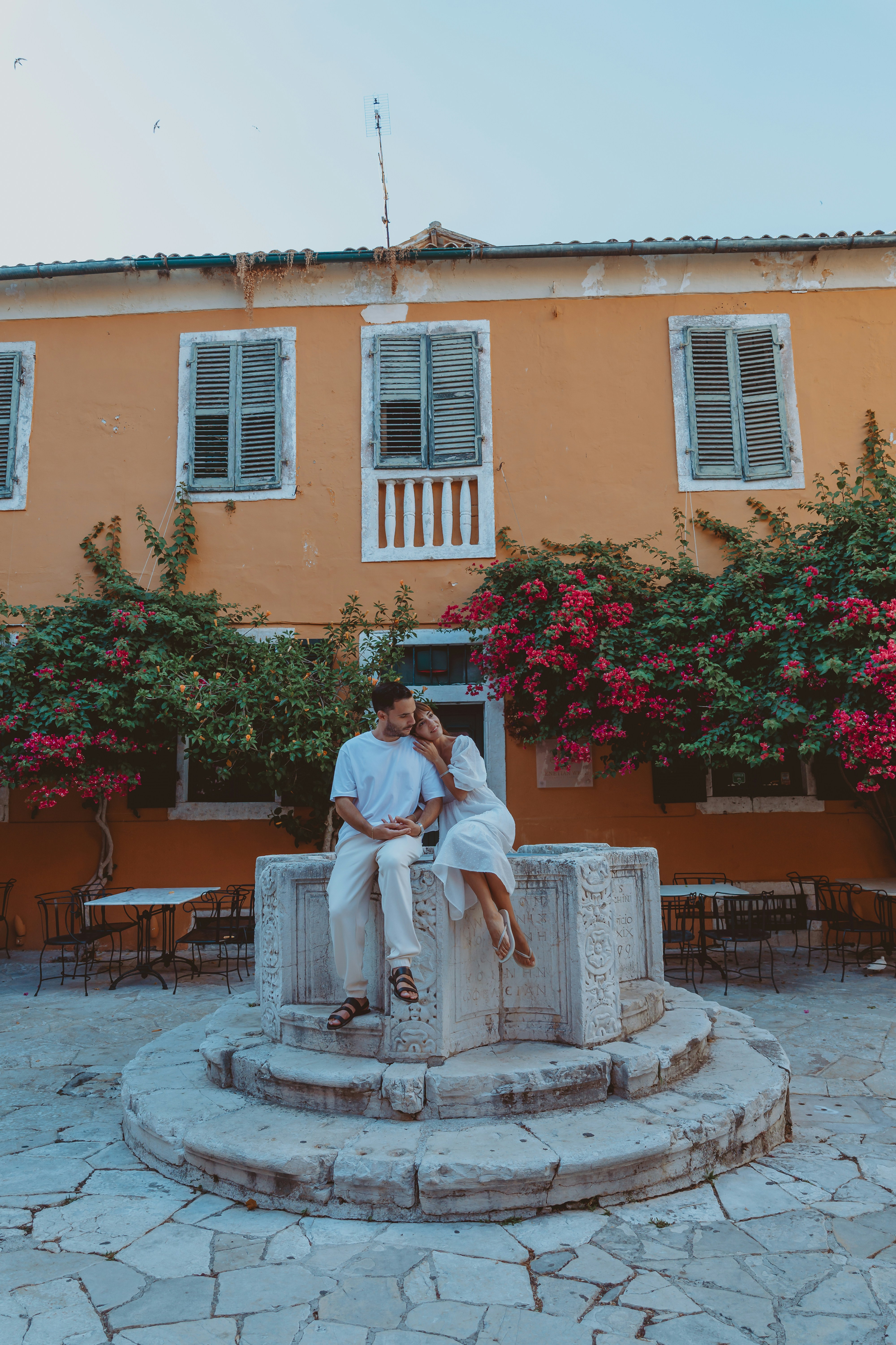 A couple cuddles in front of a yellow building. photo – Free Portrait ...