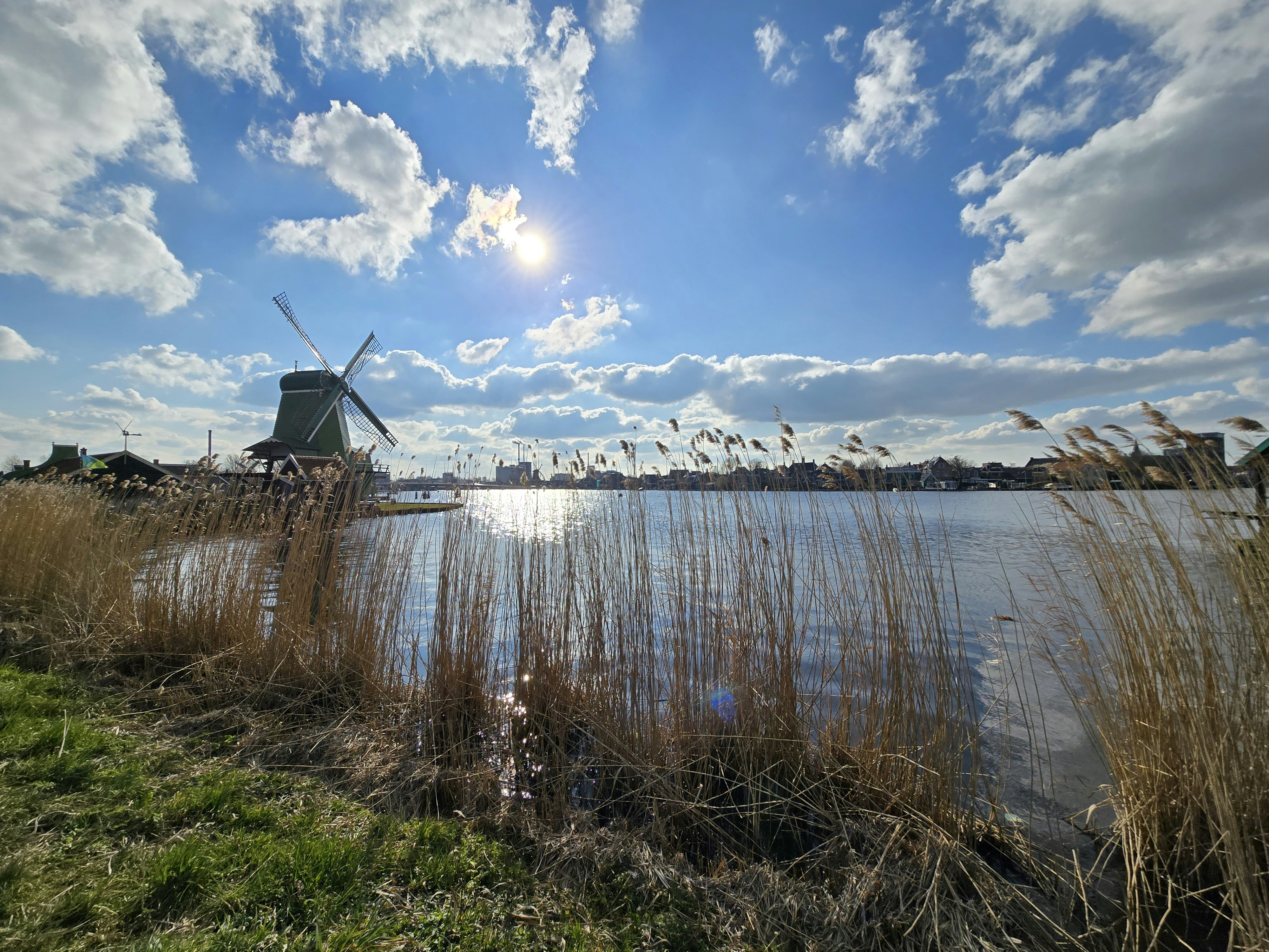 A windmill stands beside a calm body of water. photo – Free Moon Image ...