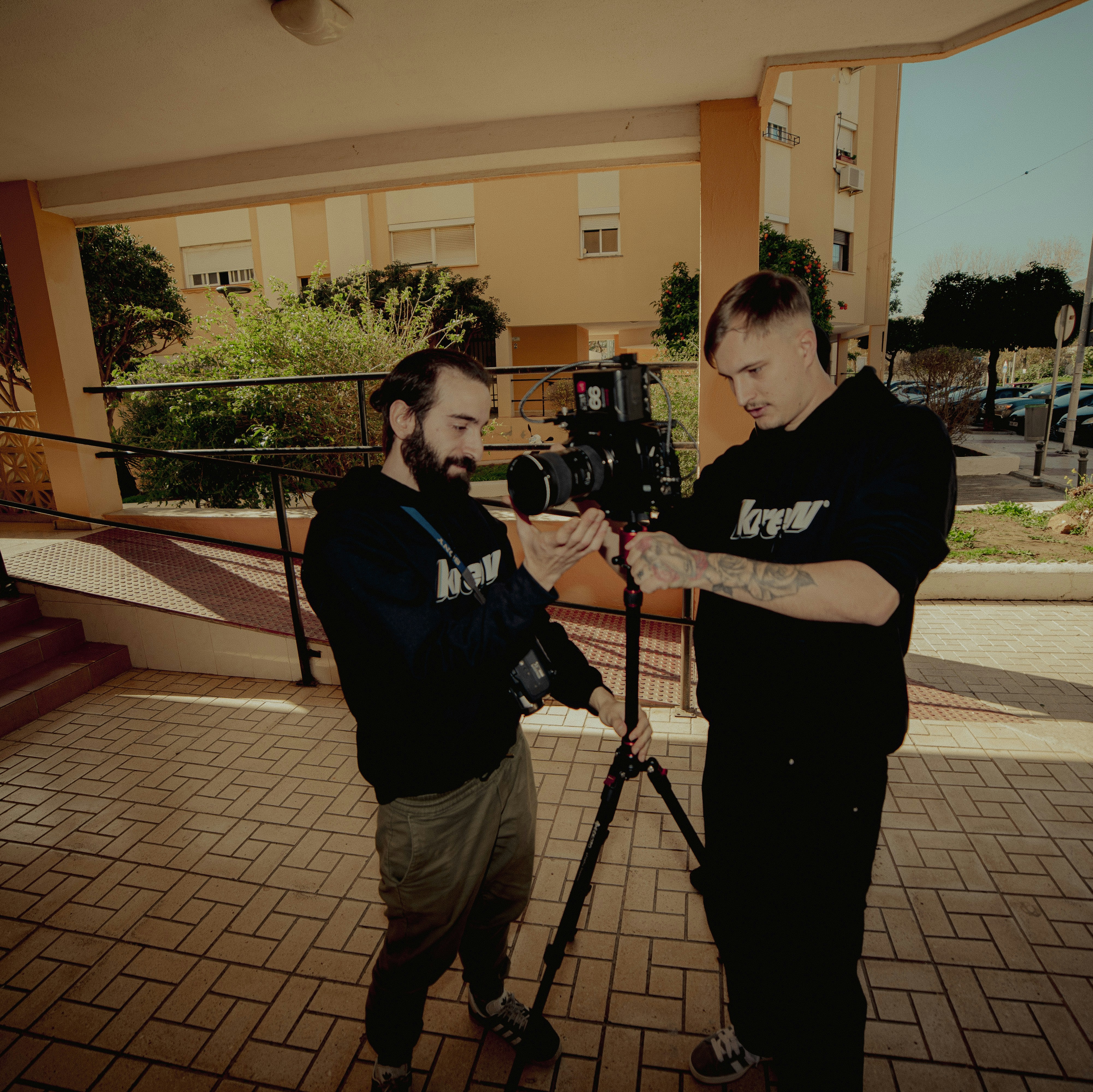 Two people are setting up a camera on a tripod. photo – Free Man Image ...