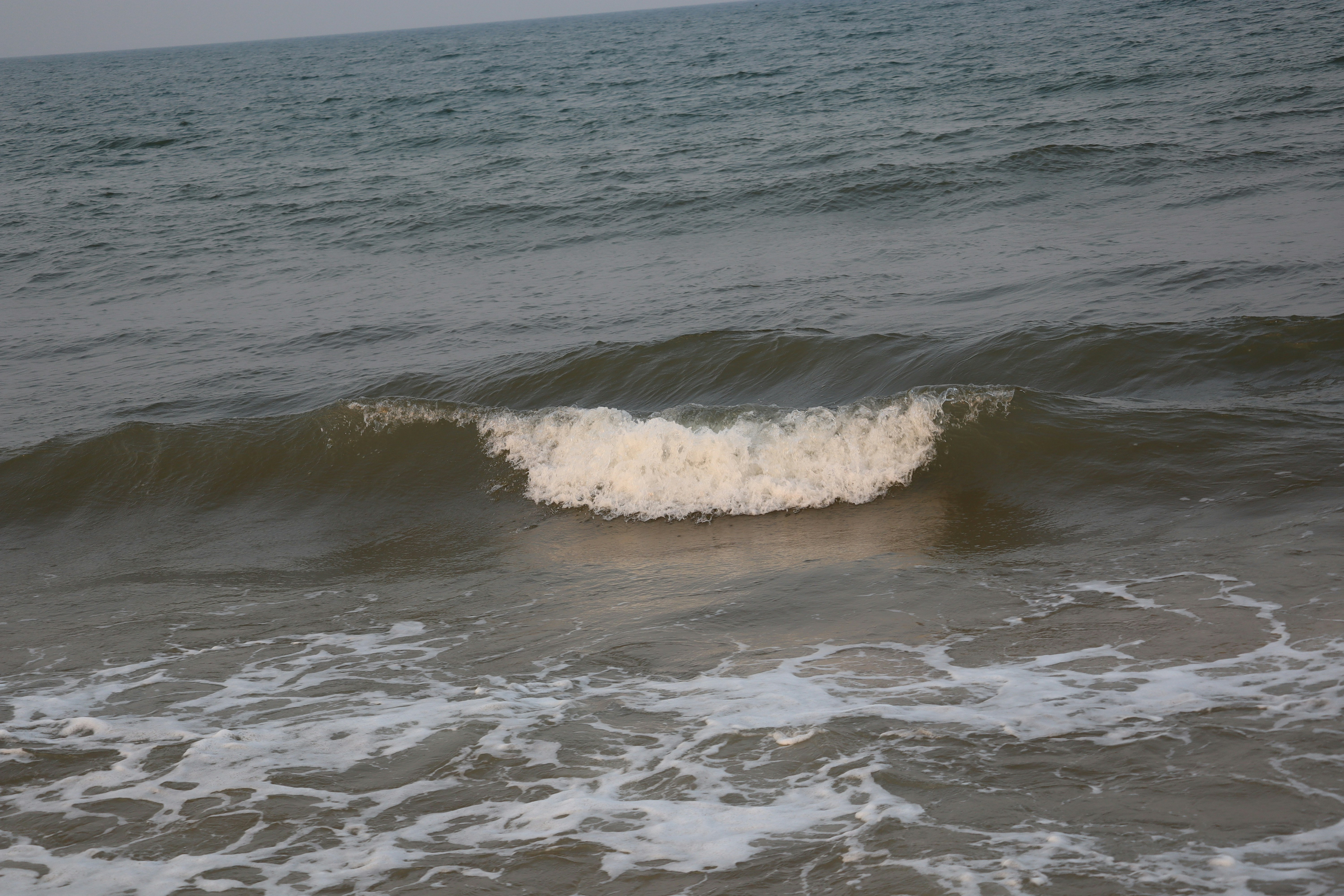 Centered Crest: A Quiet Sea's Small Wave in Foamy Light