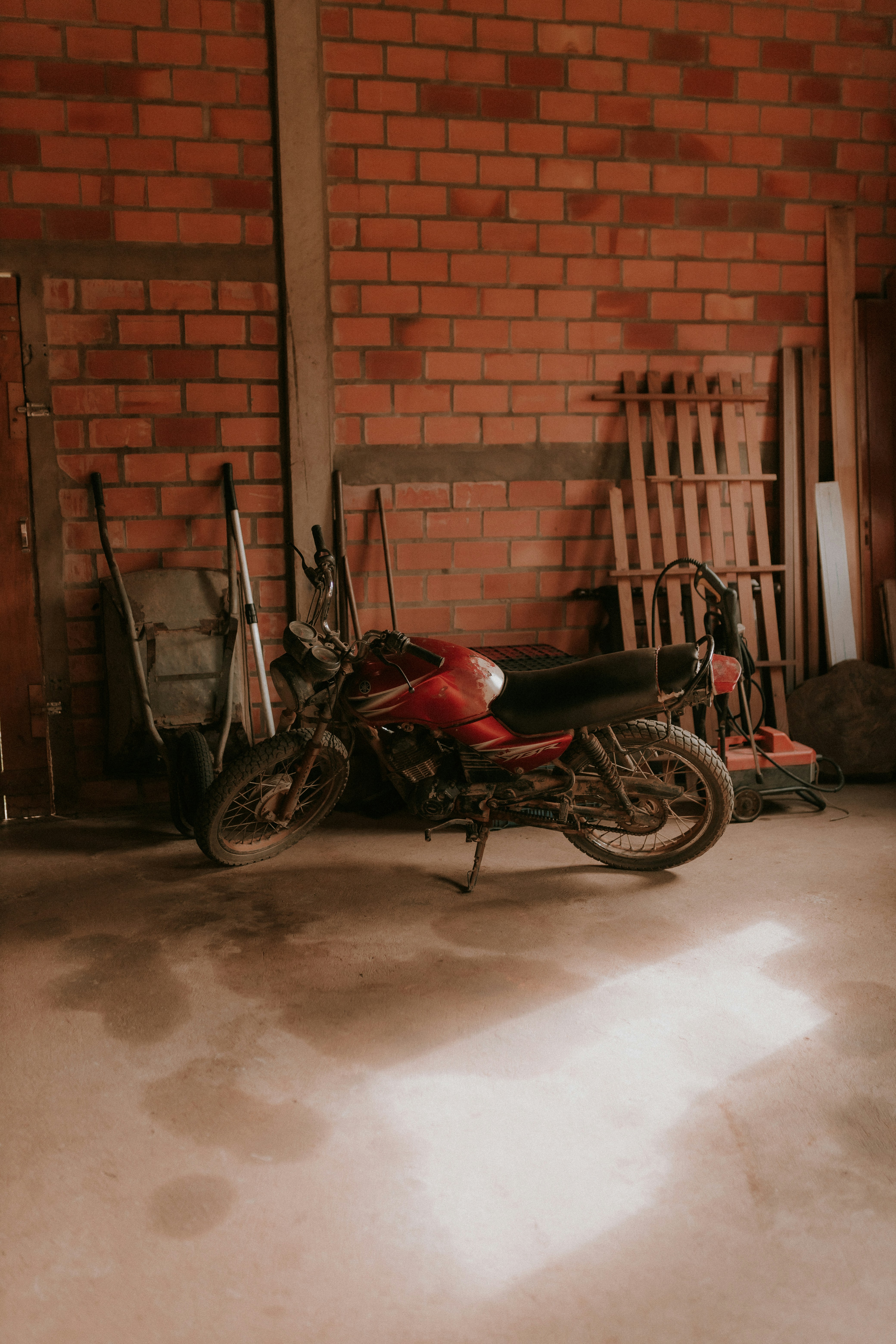 A red motorcycle parks in a brick-walled garage. photo – Free Wall ...