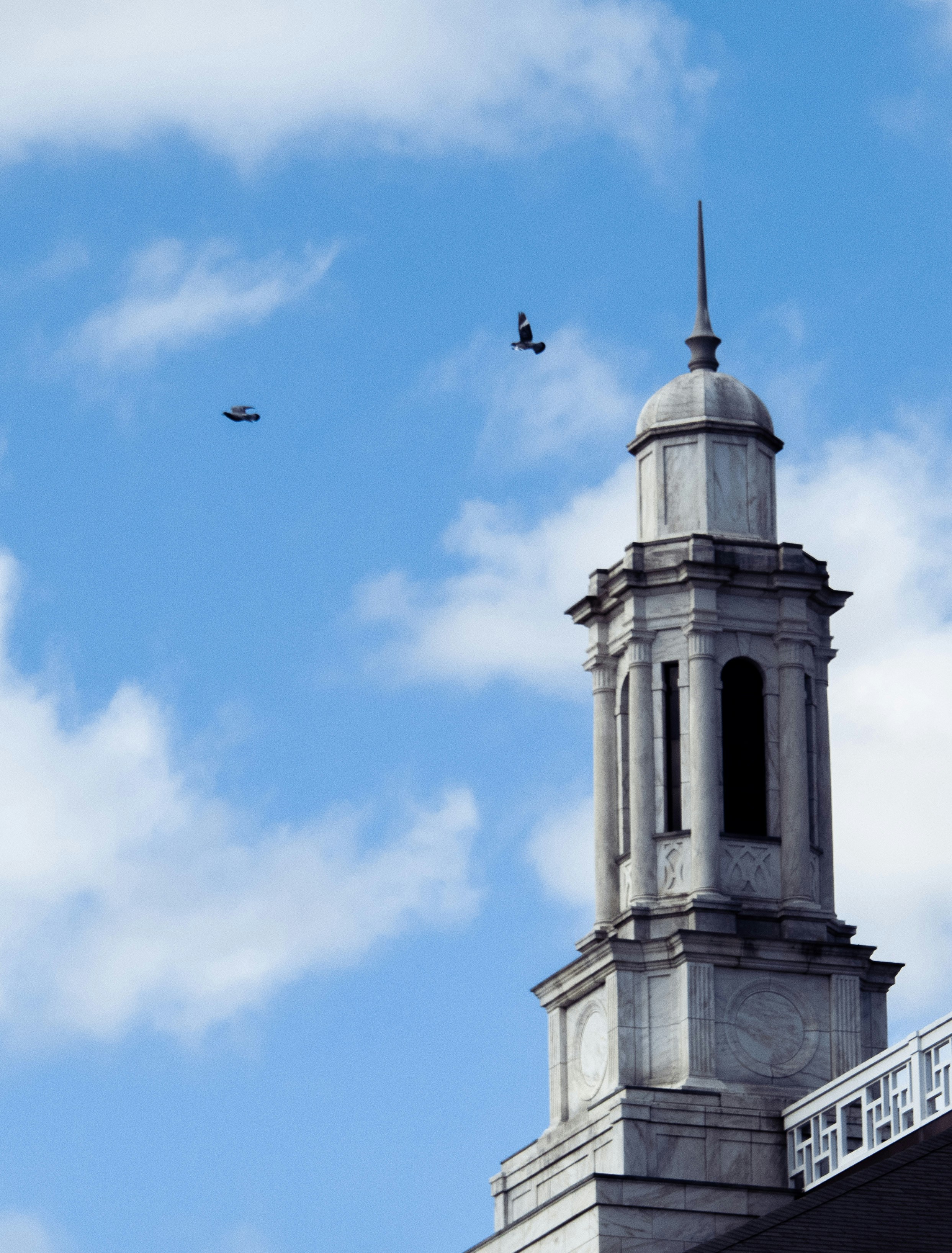 Cerulean Sky Framing a Marble Spire with Two Birds in Flight