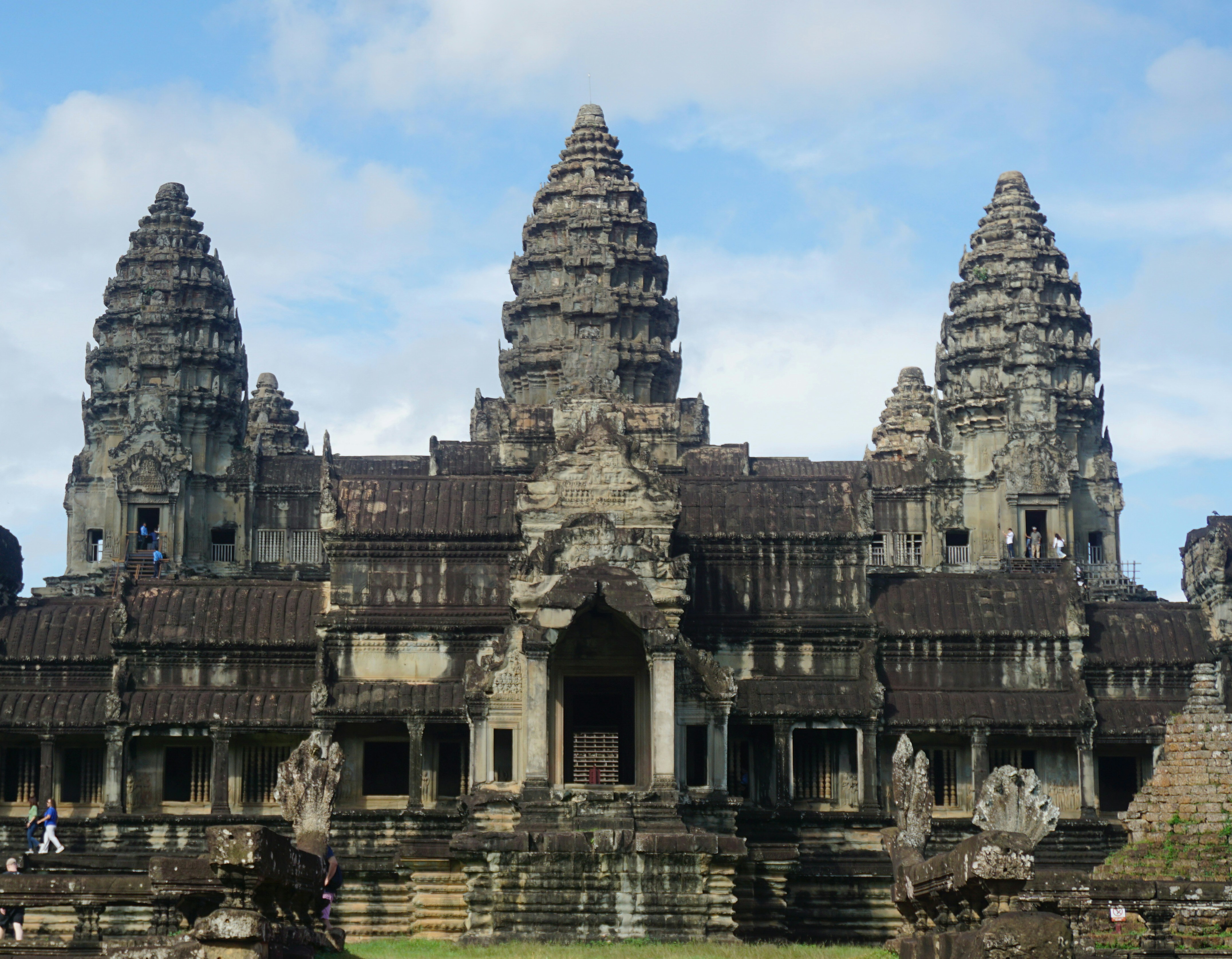 Ancient temple complex of Angkor Wat under a bright blue sky.