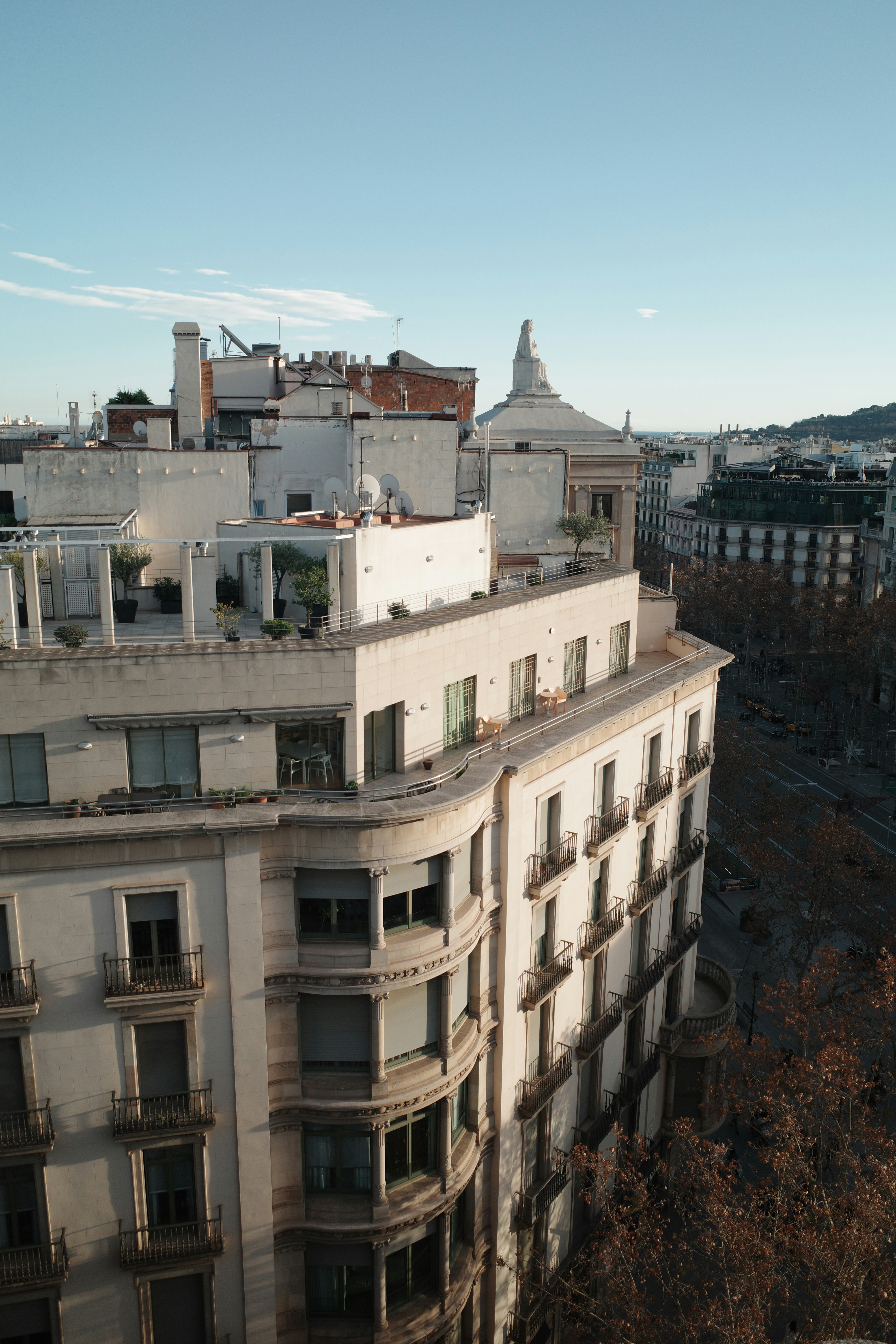 Curved facade of a city building under a clear blue sky, surrounded by urban landscape.
