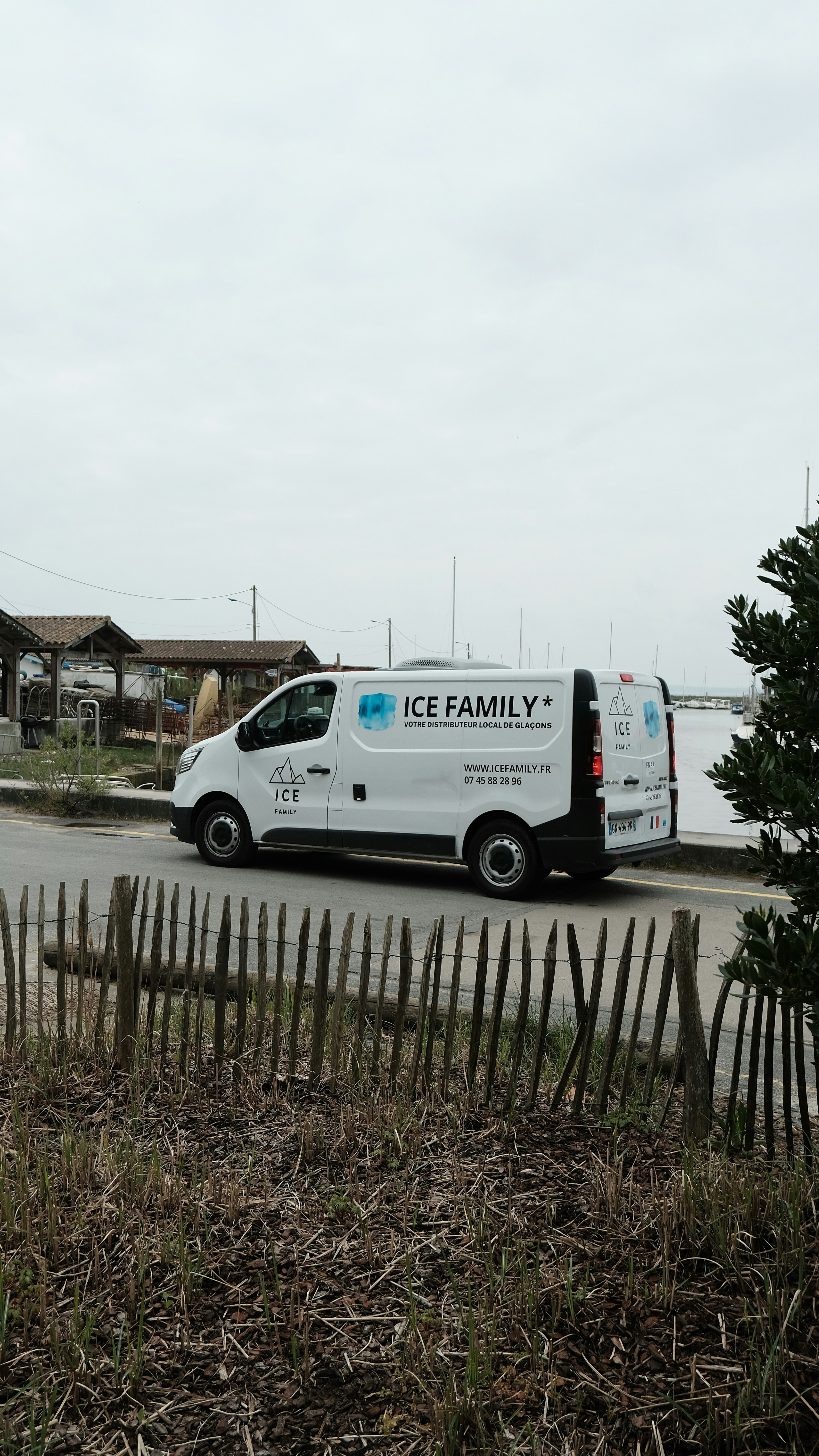 Ice Family van beside a weathered fence: a quiet coastal service stop