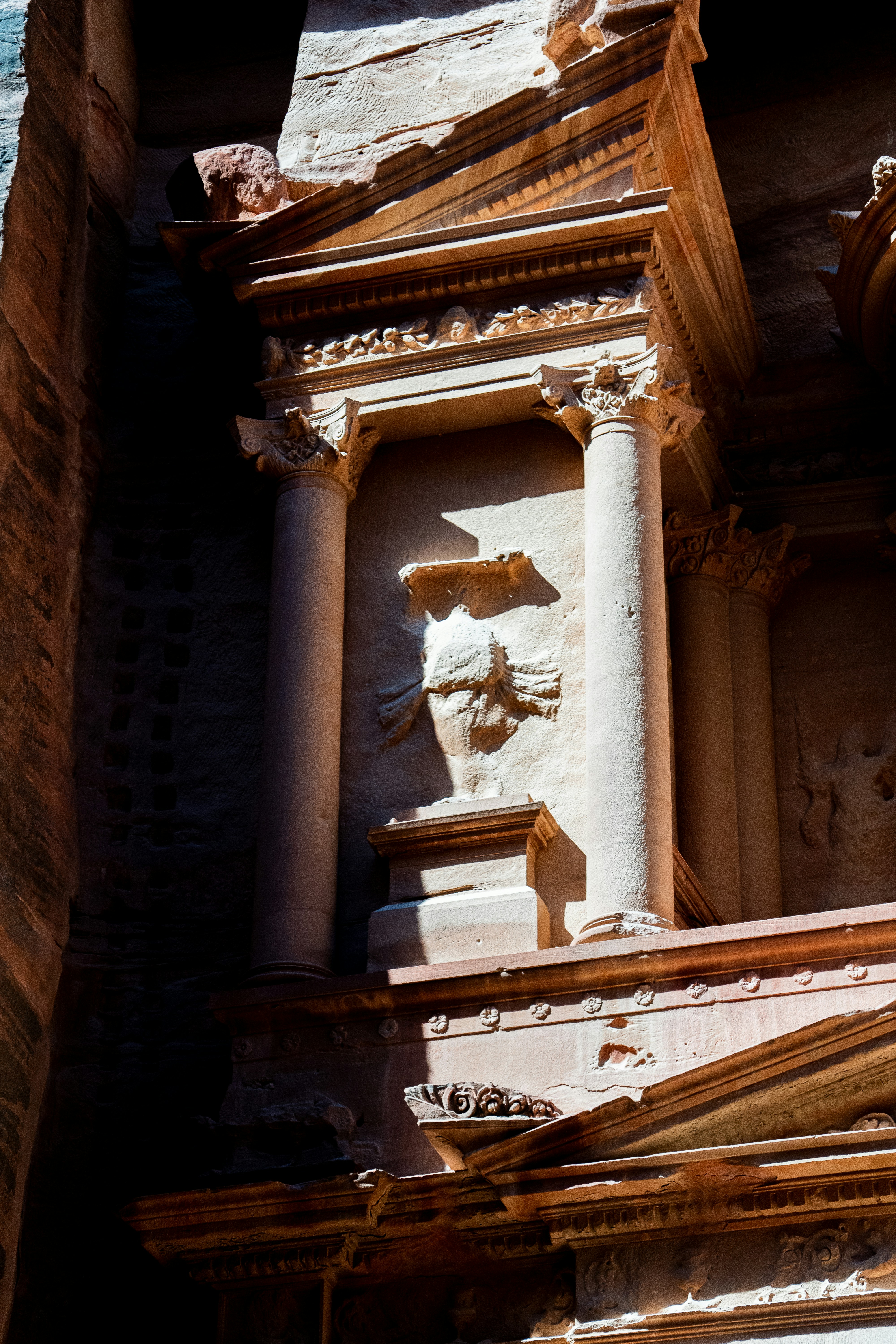 Intricate stone carving of a figure set against a sunlit rock face, showcasing the artistry of an ancient civilization.