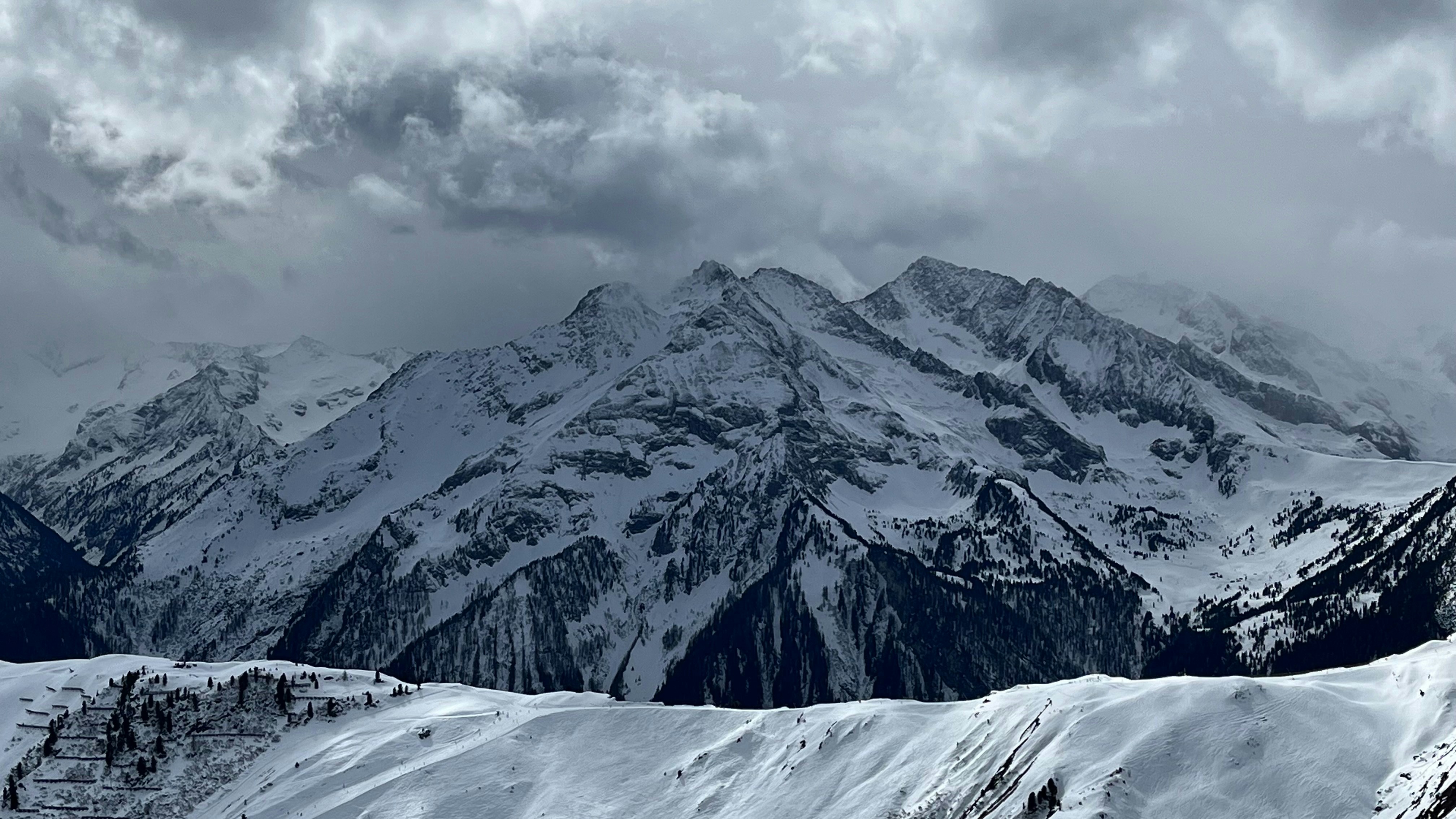 Snow-covered mountains beneath a dramatic, cloudy sky.