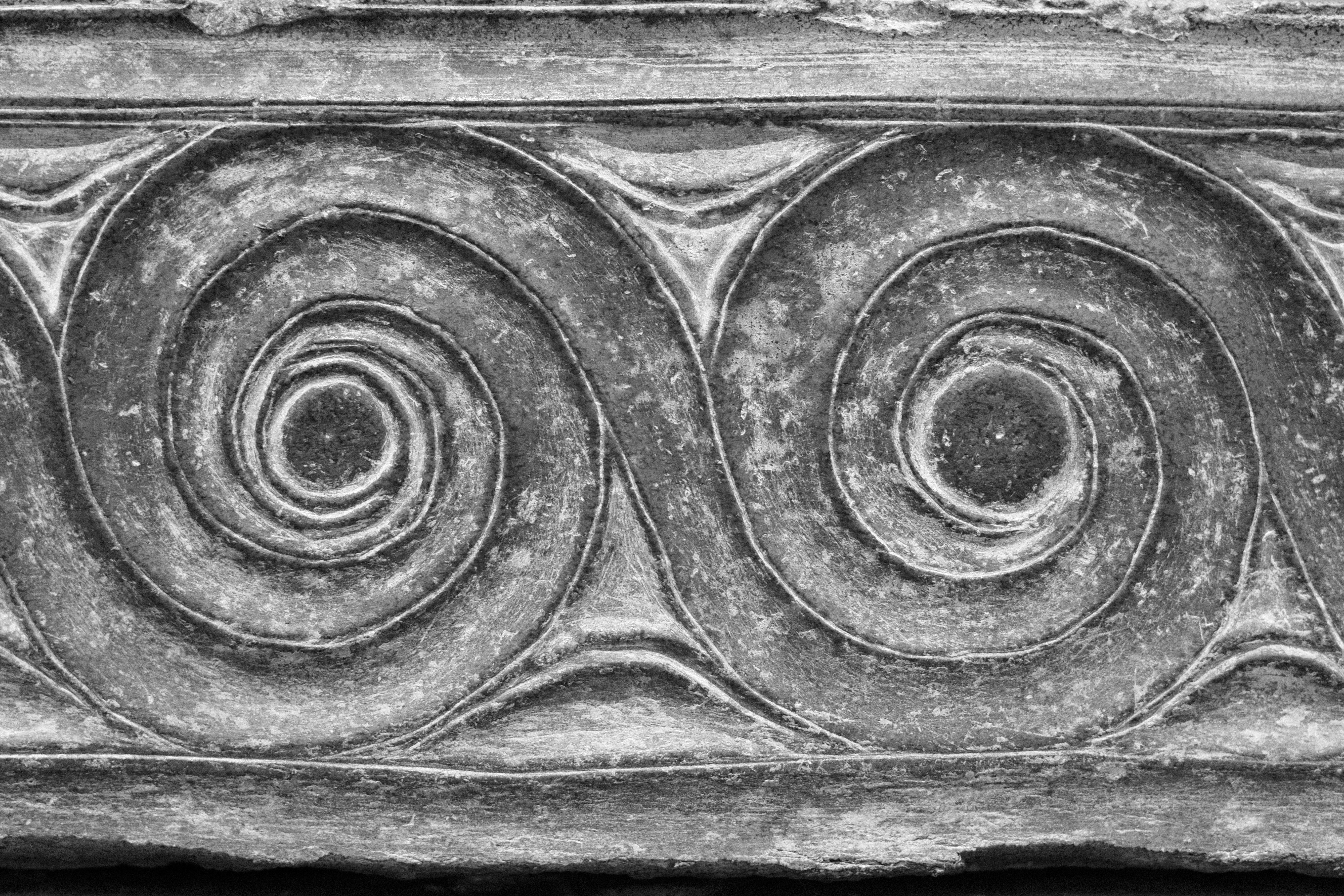 Intricate stone carving featuring swirling patterns, showcasing the artistry of ancient sculptors. The design embodies a sense of continuity and elegance.