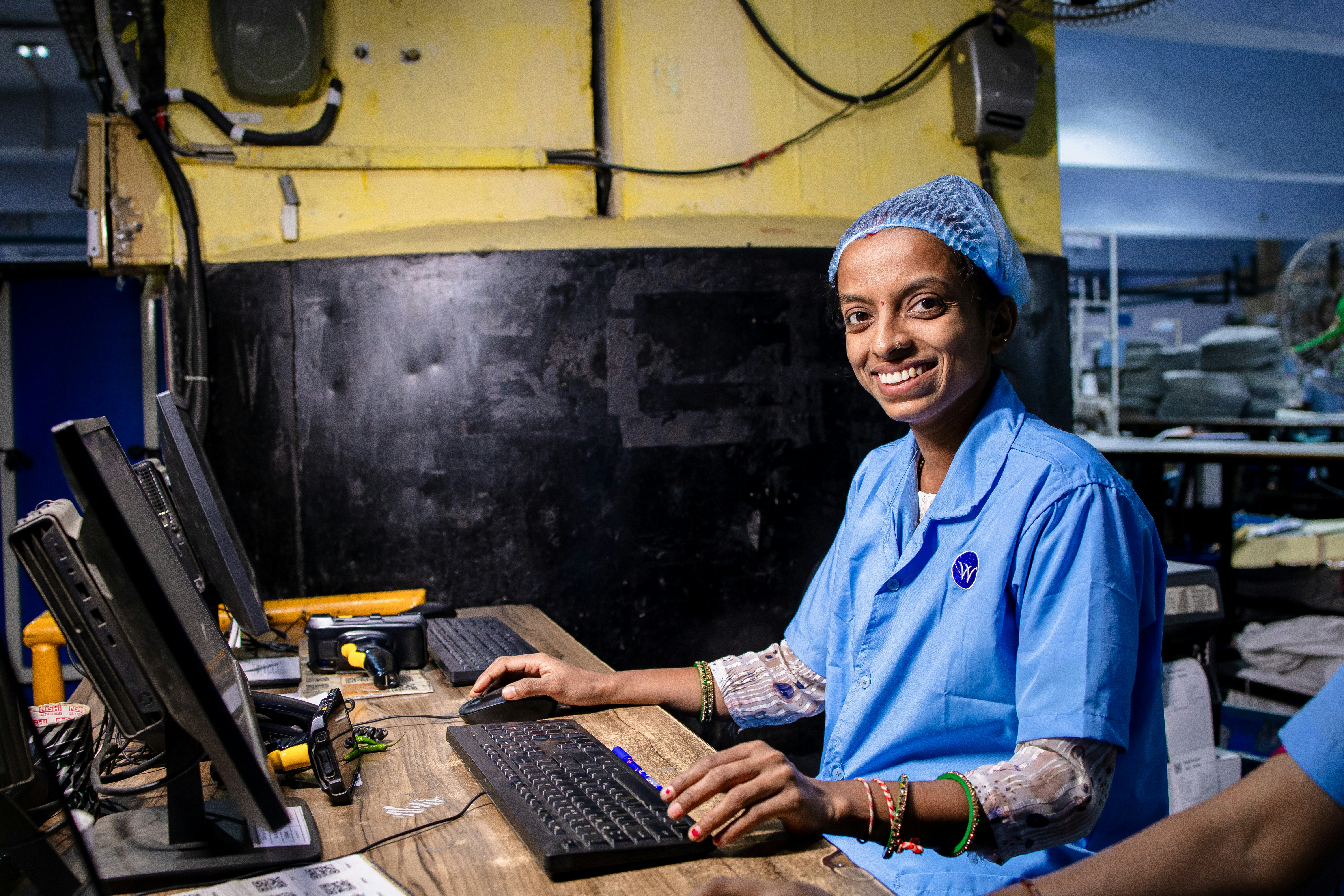 Woman in uniform smiles while using a computer. photo – Free Blue Image ...