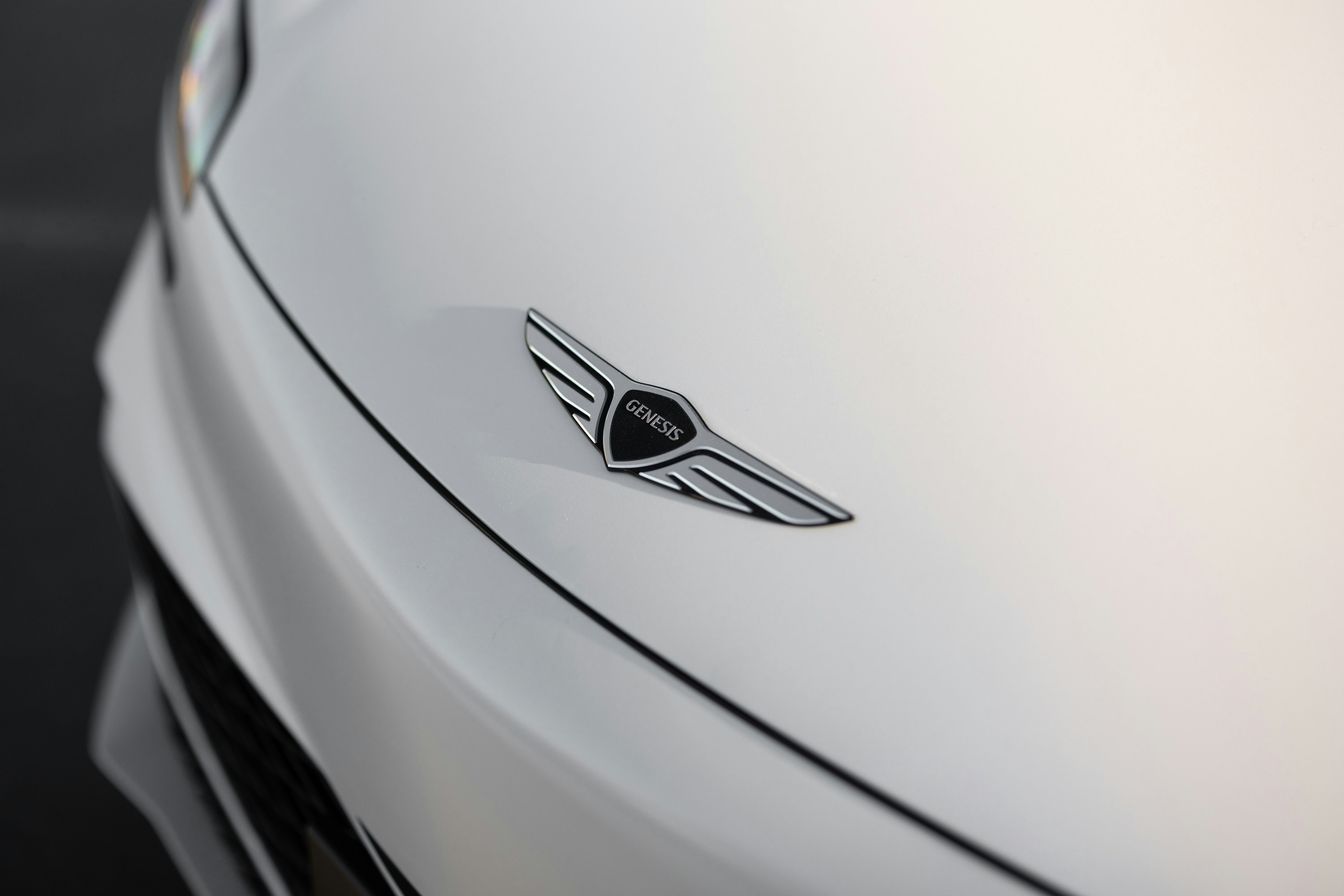 A genesis emblem rests on a white car's hood. photo – Free Electric car ...