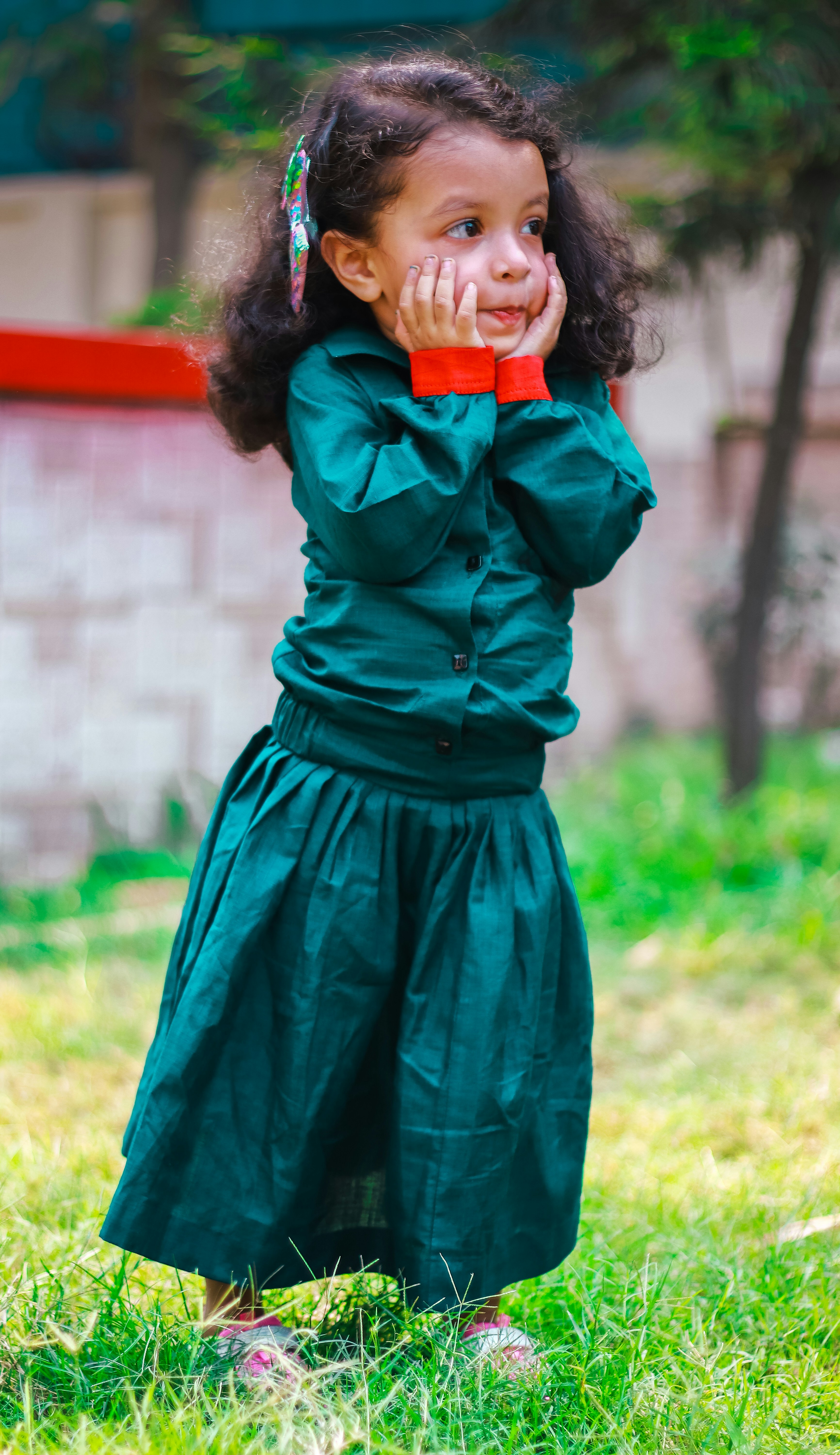 A young girl poses outdoors, touching her cheeks. photo – Free Portrait ...