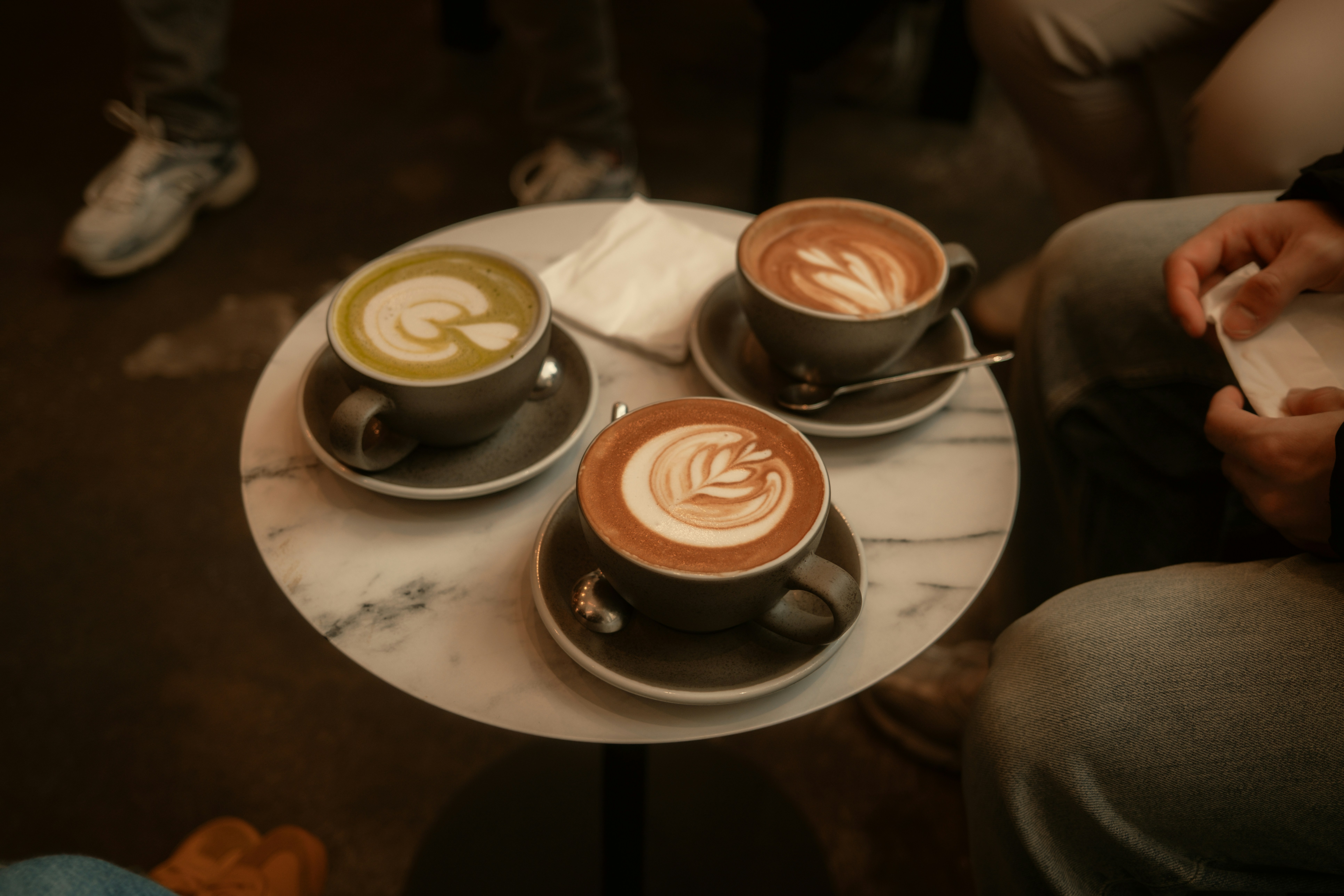 Three lattes sit on a table with a decorative design. photo – Free ...