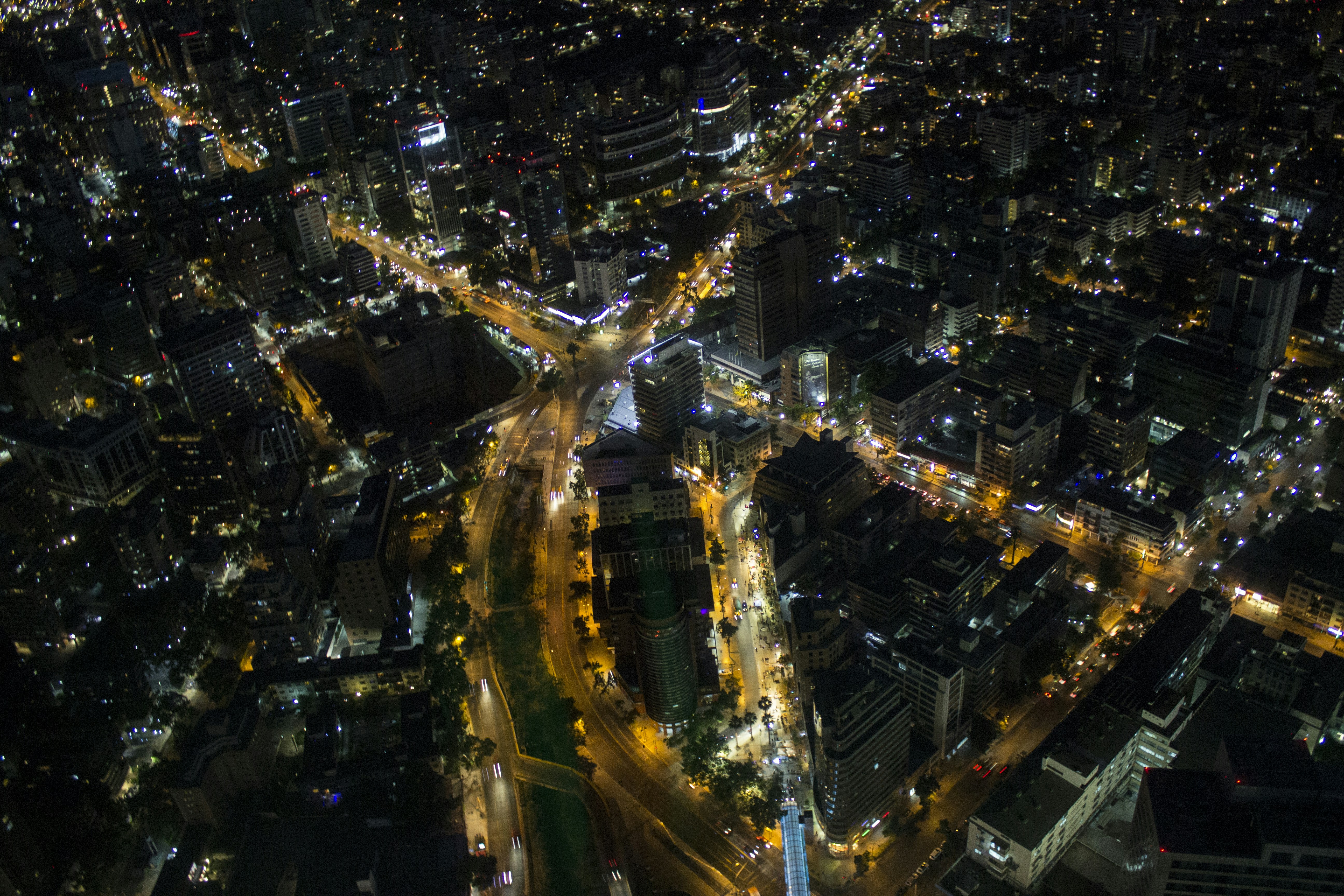 Aerial view of a city intersection illuminated by streetlights and car trails at night.