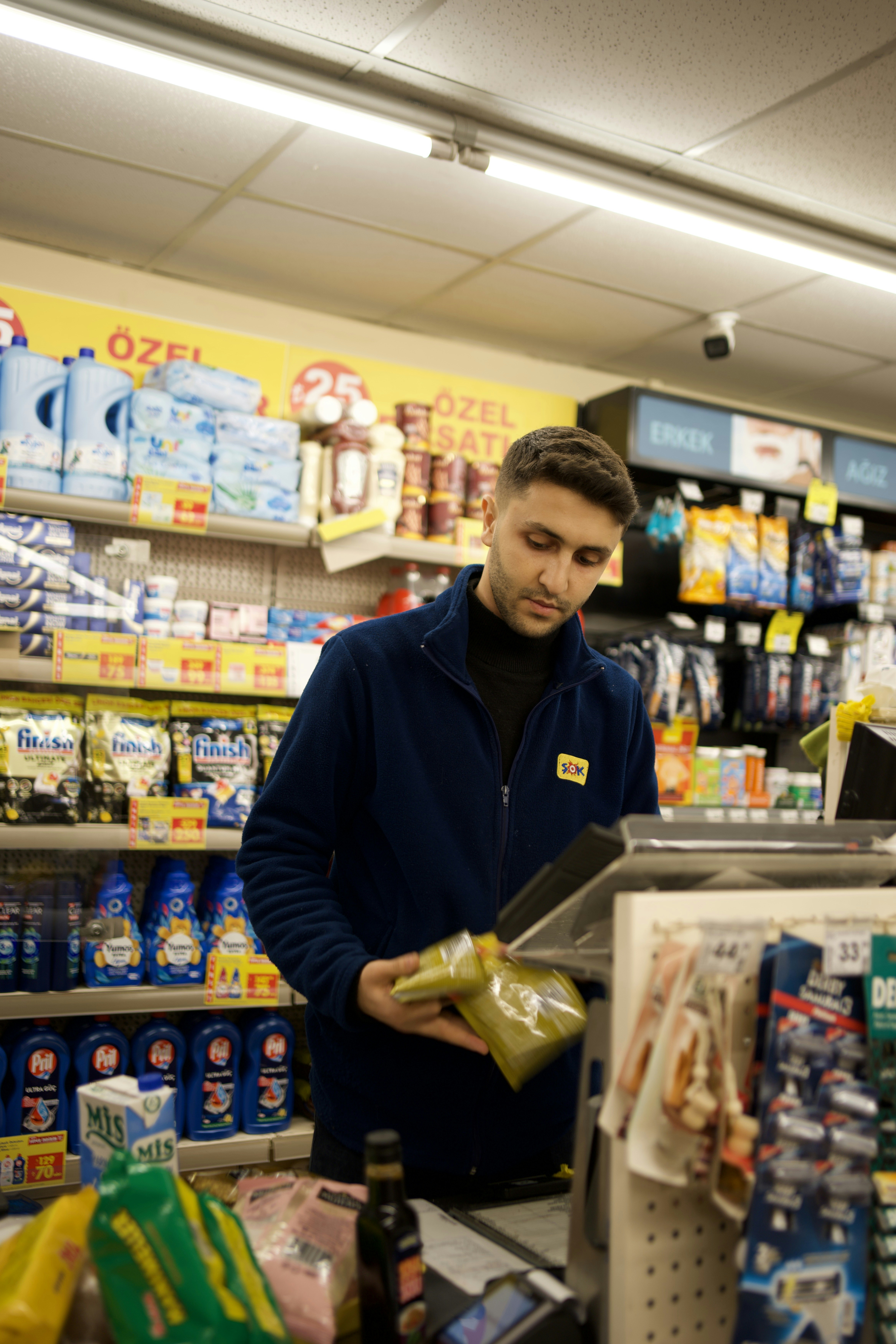 Checkout Quiet: A Focused Clerk in a Busy Grocery Aisle