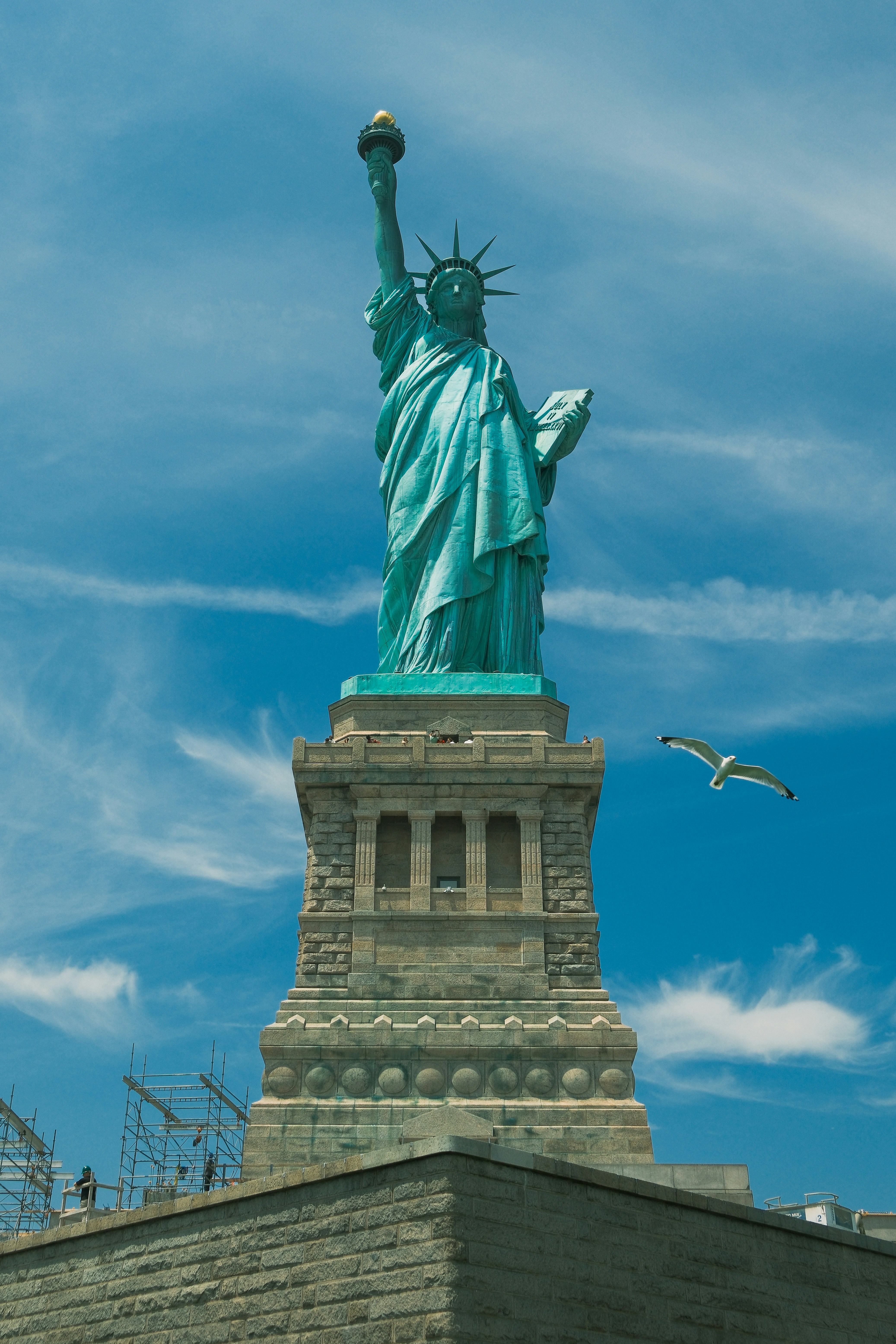 The statue of liberty stands tall against a blue sky.
