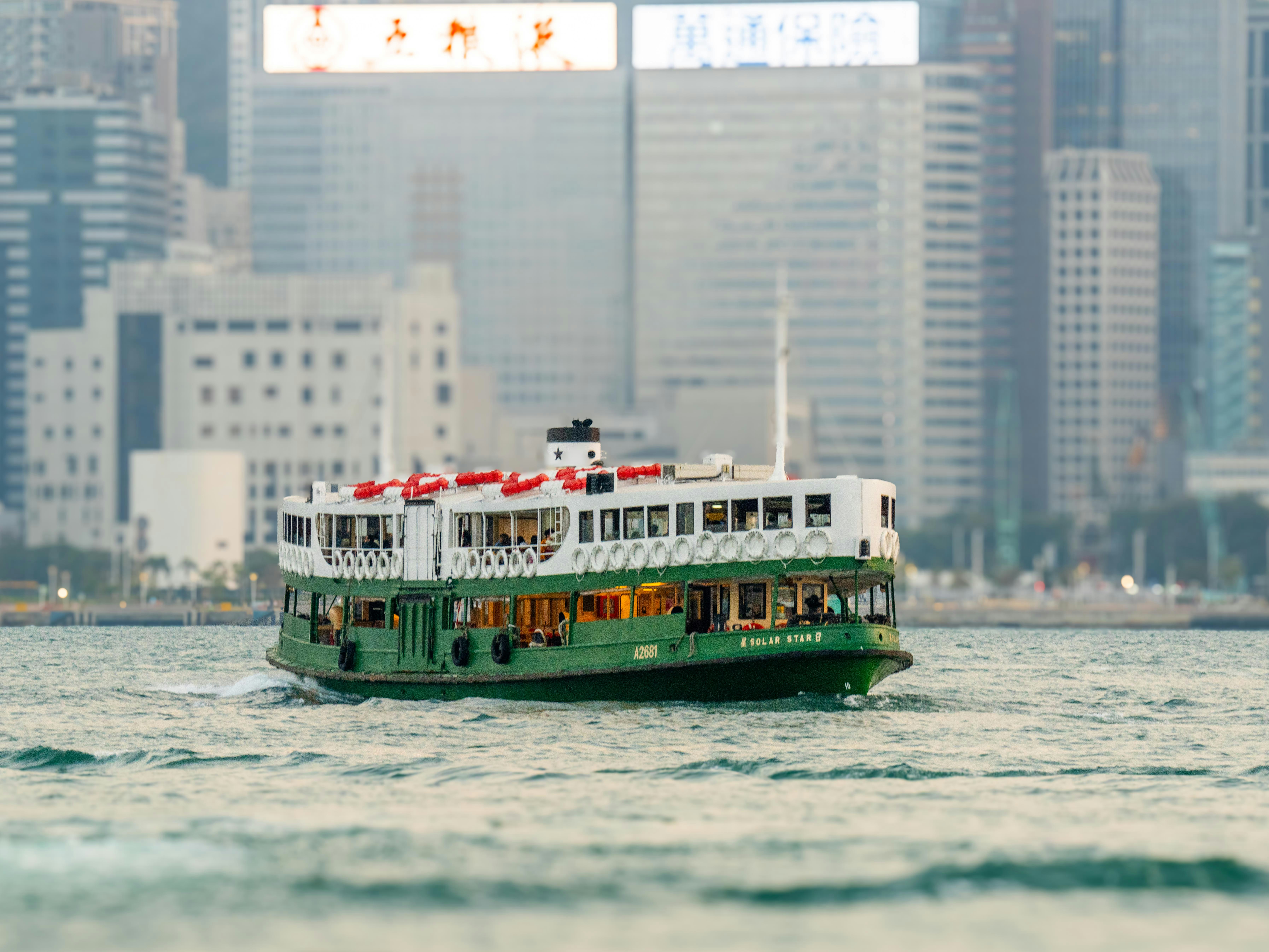 A green ferry sails in front of a cityscape. photo – Free City Image on ...