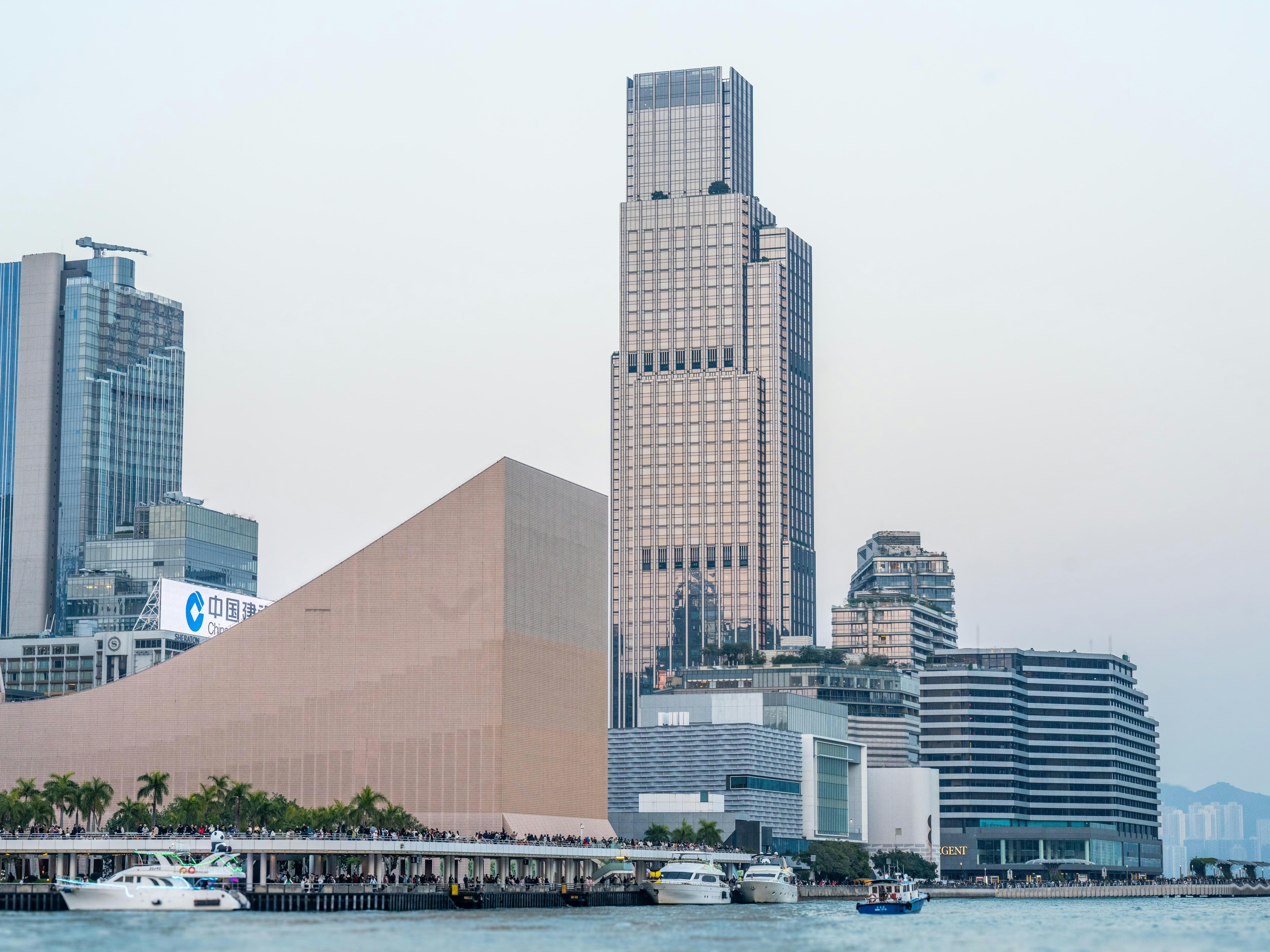 Modern skyscrapers by the waterfront under a clear sky at dusk.