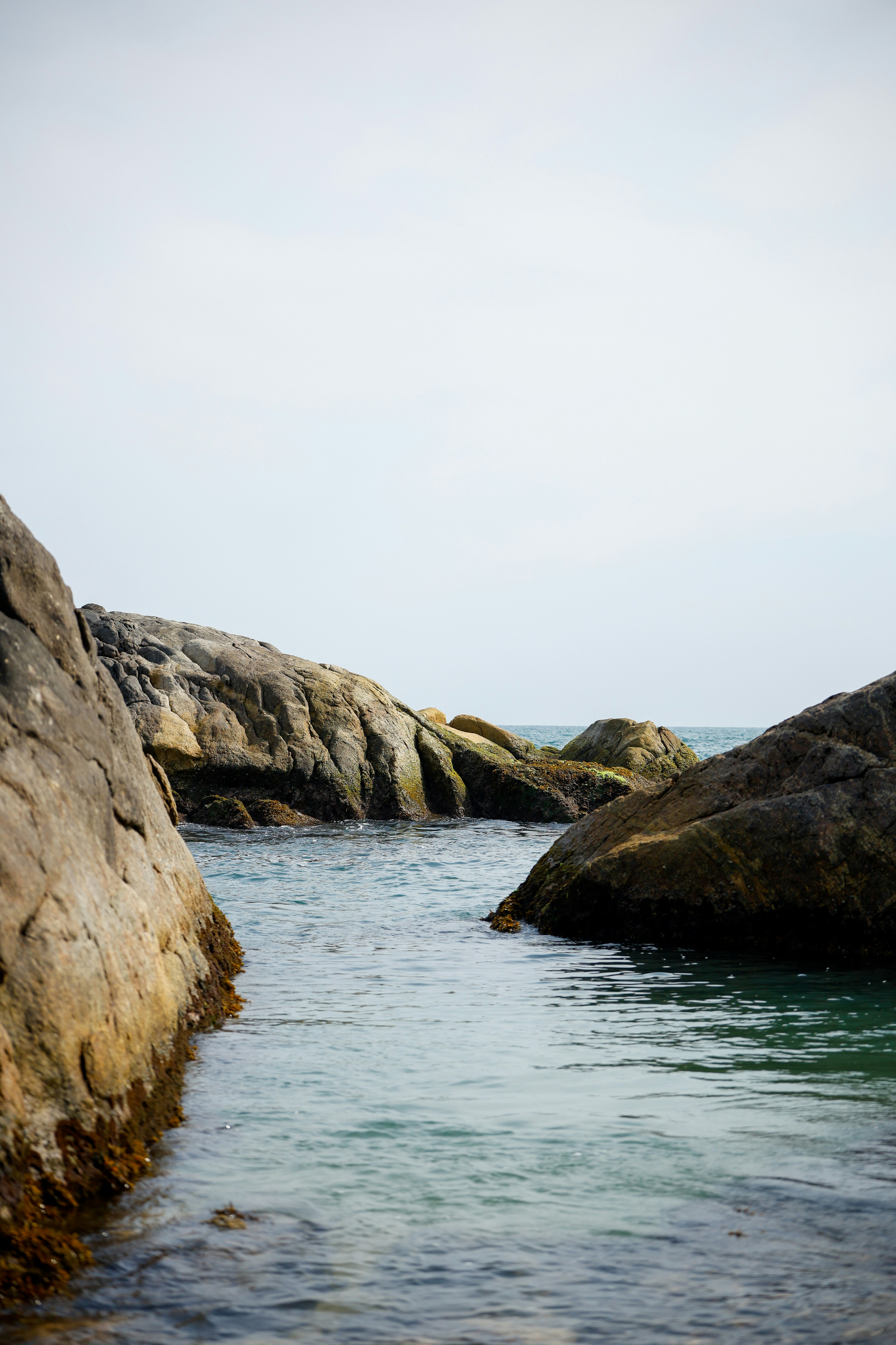 Rocky shoreline with gentle waves under a cloudy sky.