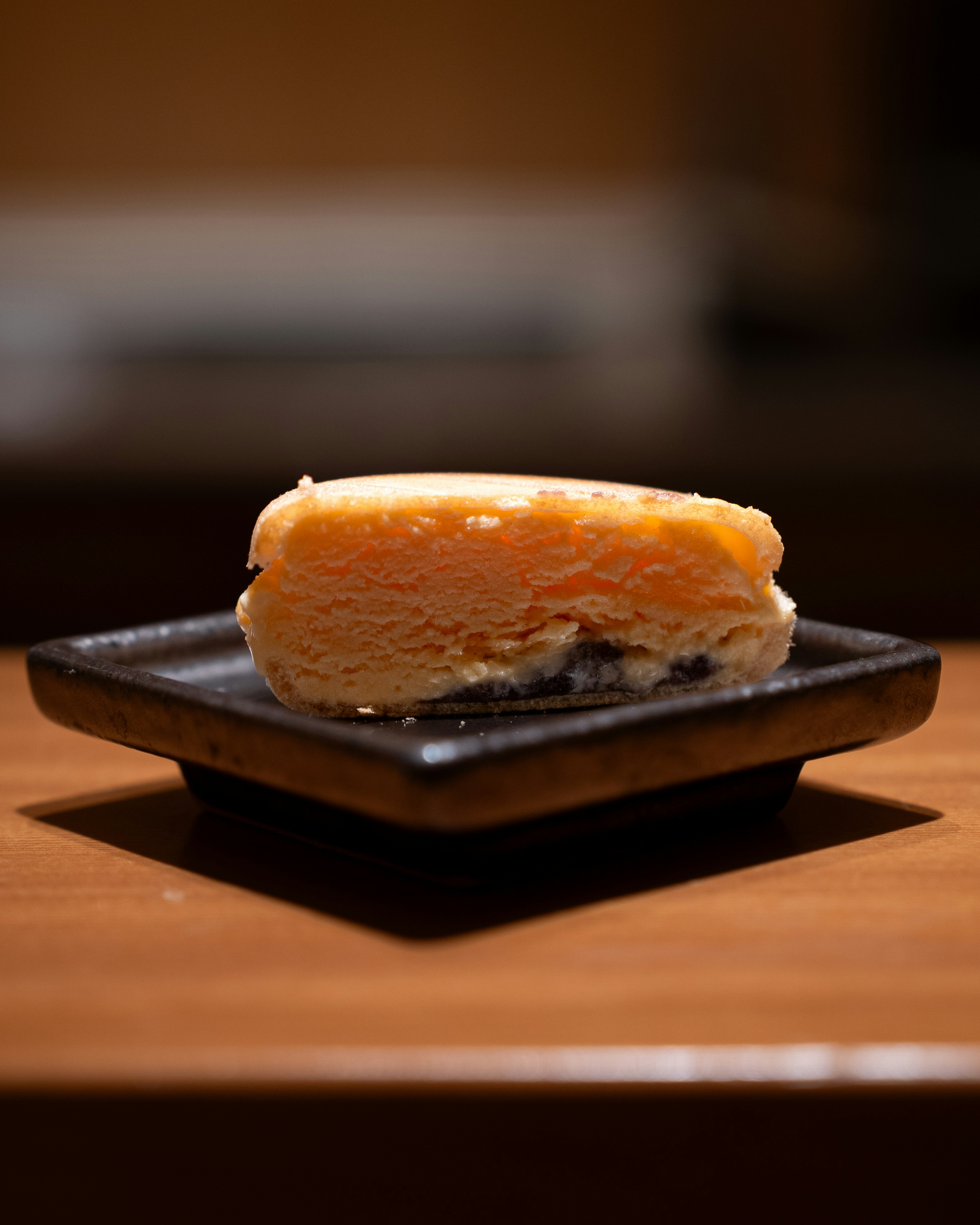 Mango-Tinted Cheesecake Slice on a Matte Black Plate
