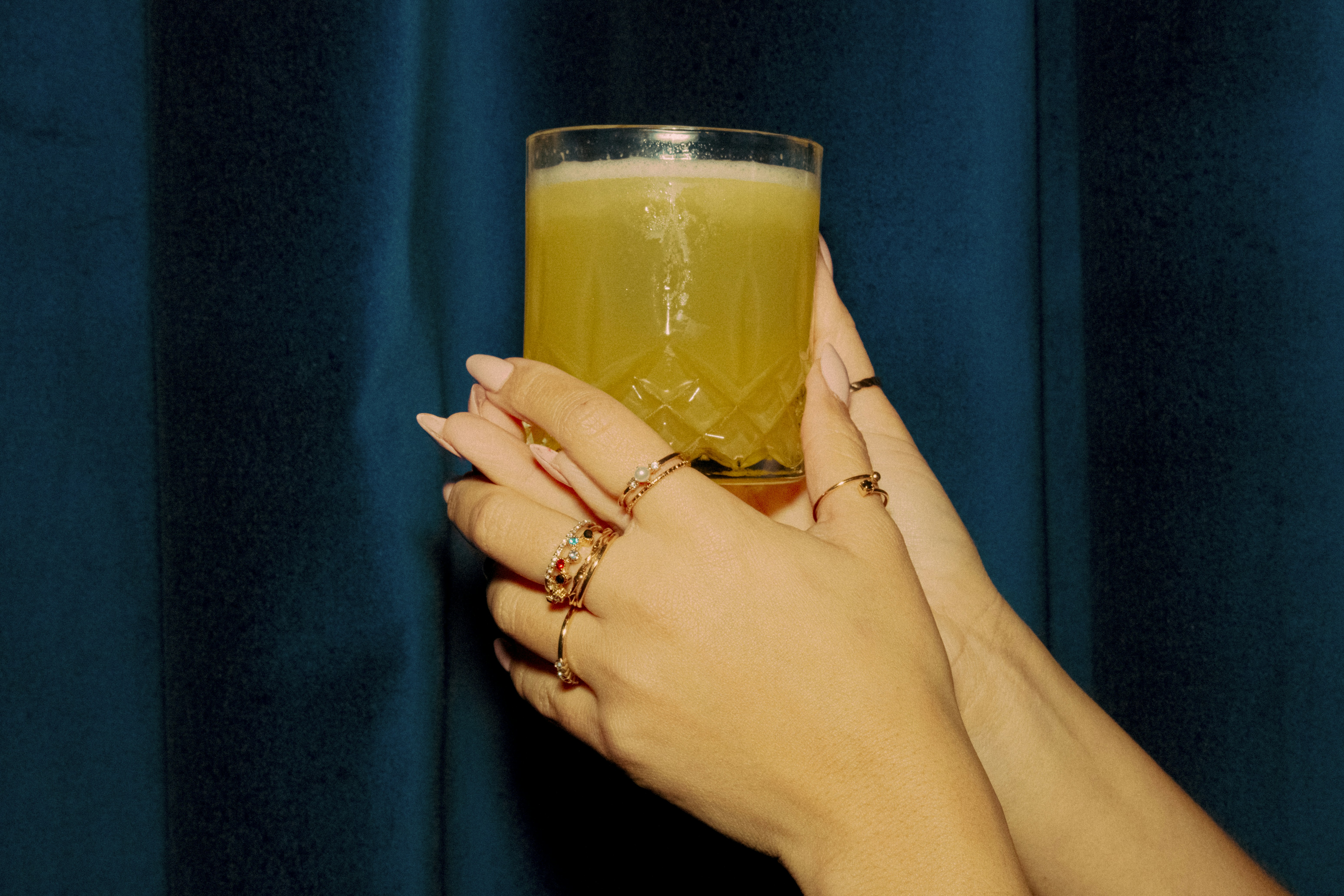 Amber Glass in Velvet Blue: Hands with Rings Framing a Moment