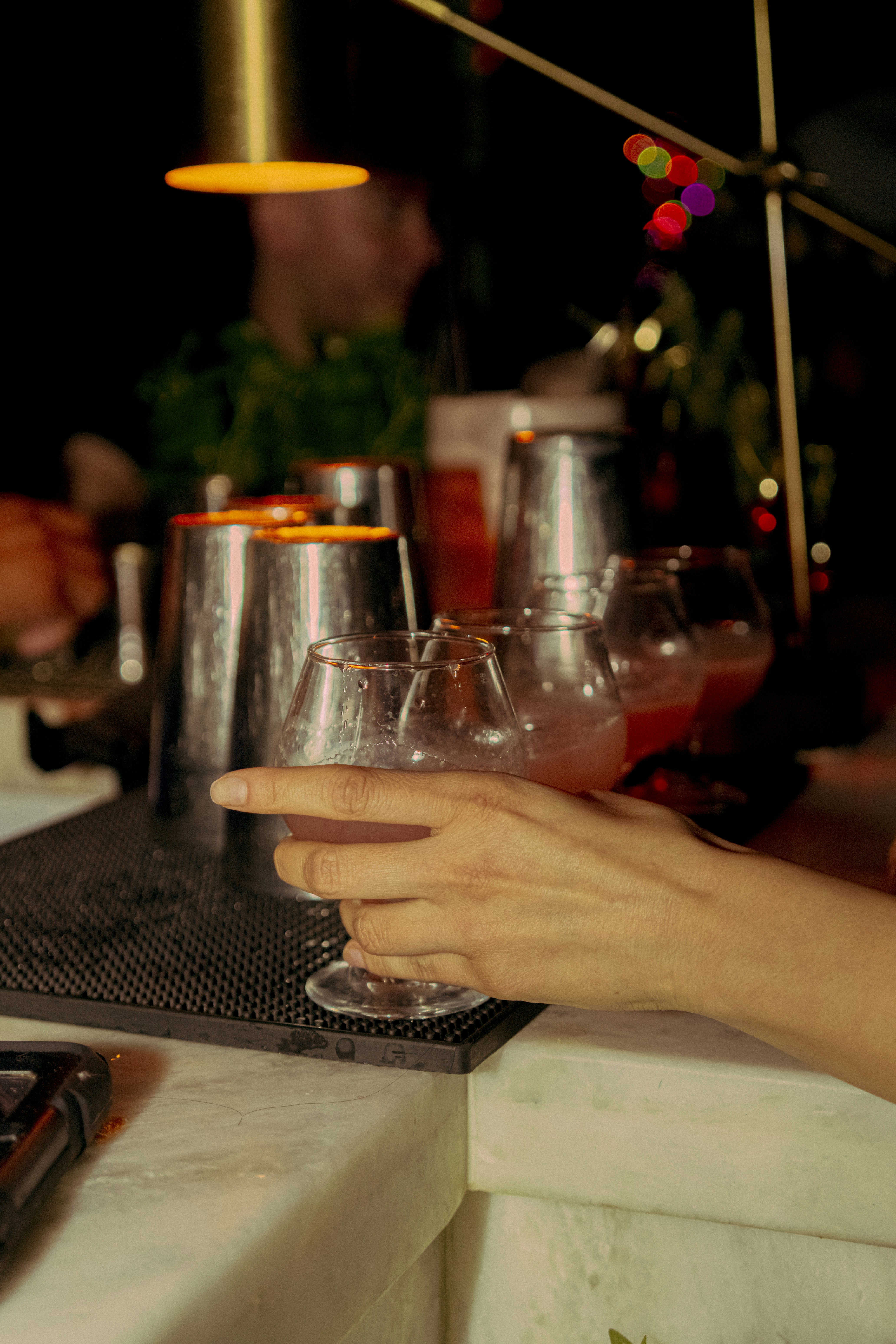 Crystalline Pink in a Warm Bar Glow: Hand and Cocktail Close-Up
