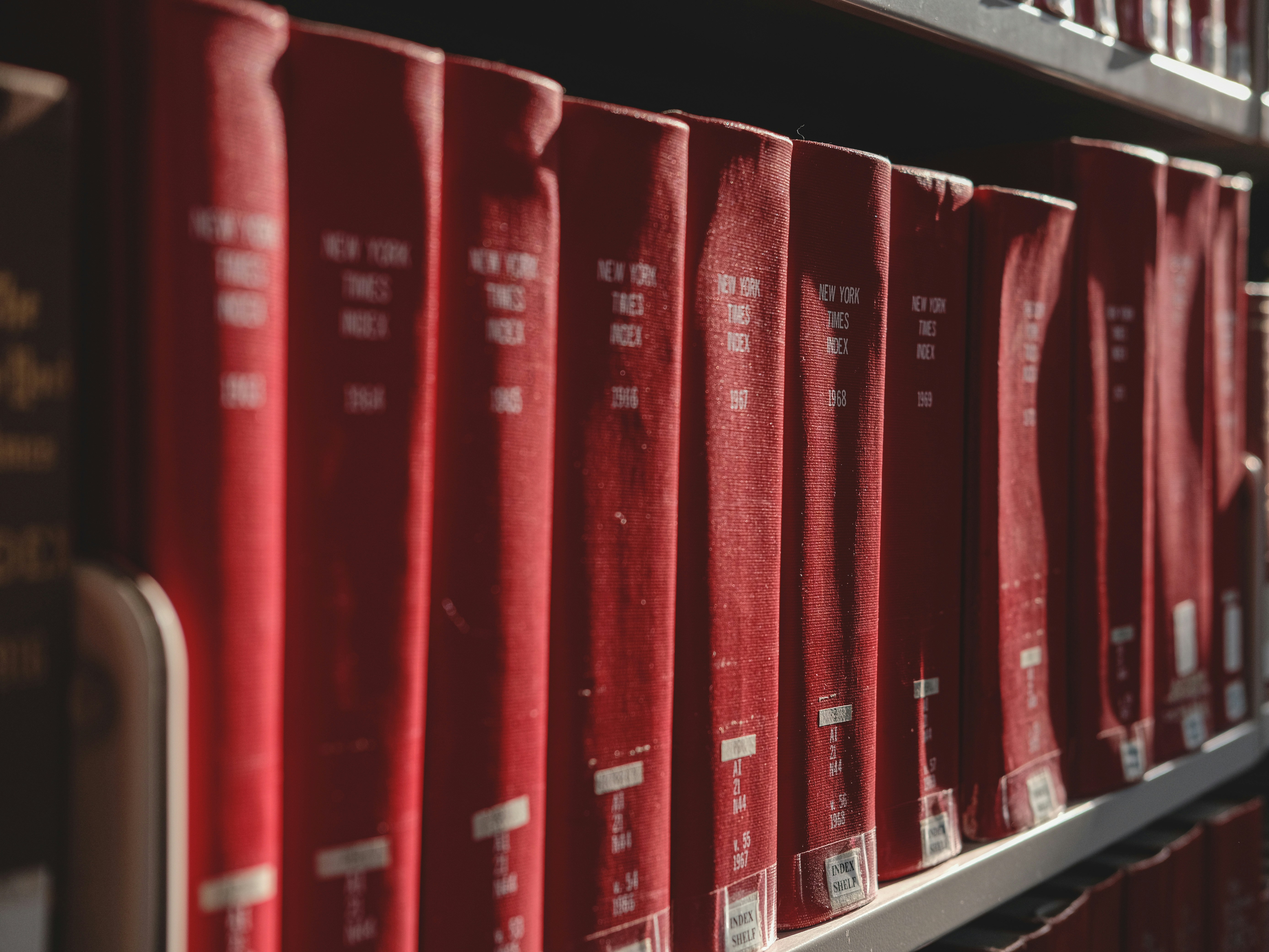 Rows of red books on a library shelf, bathed in warm, soft light.