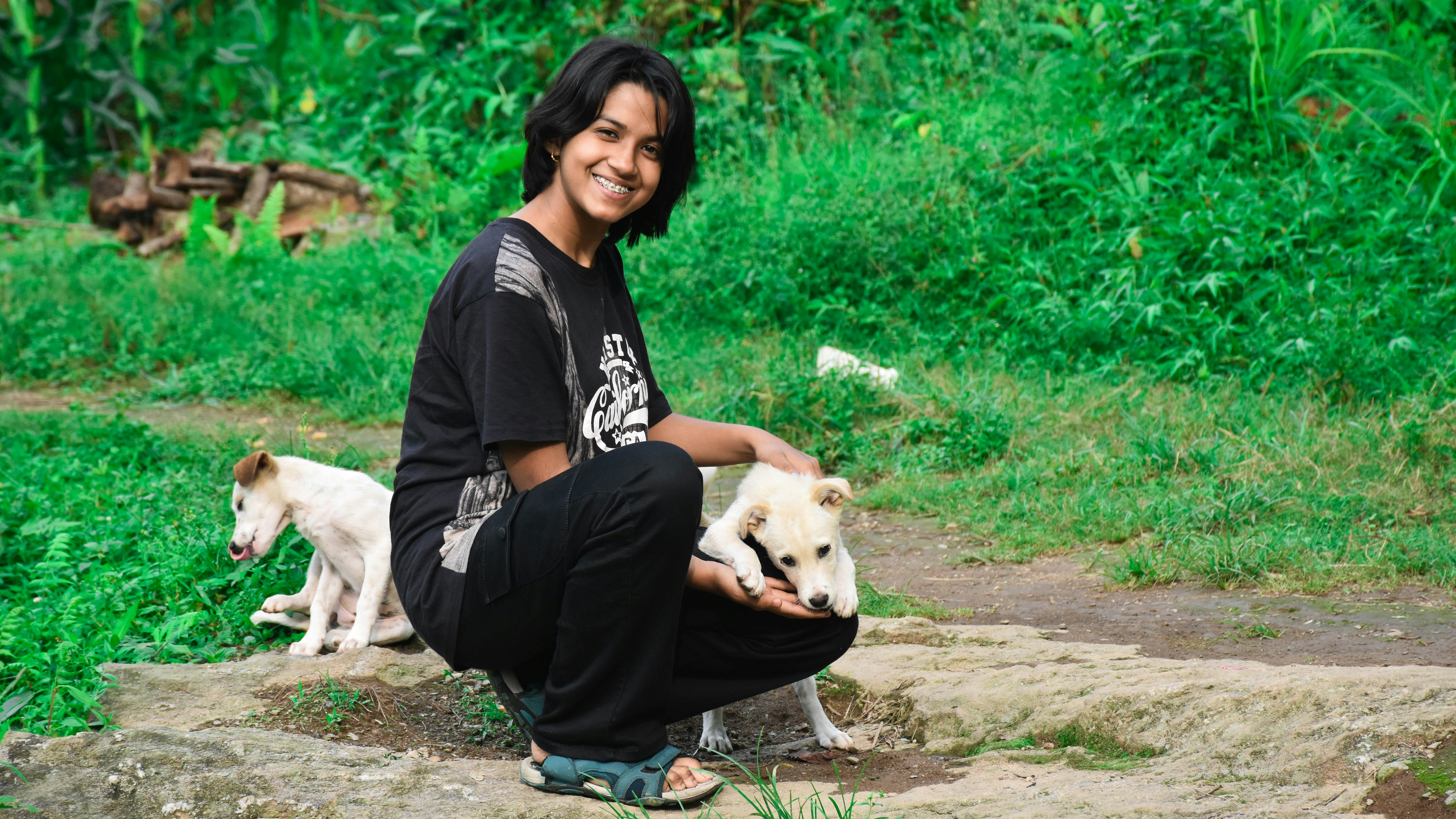 A person smiles with two dogs outdoors. photo – Free Portrait Image on ...