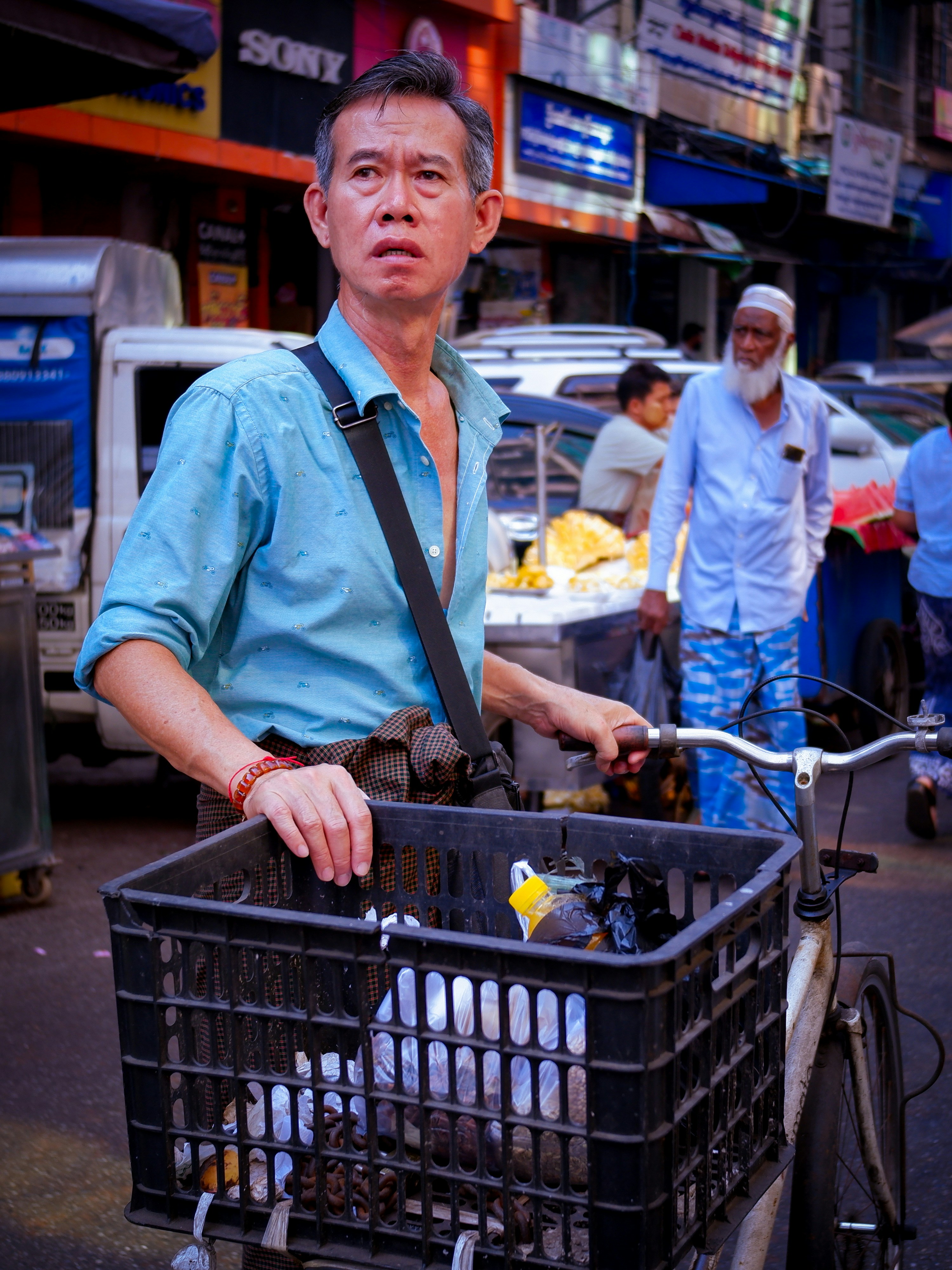 Street Vendor in Focus: The Cyclist’s Gaze Down a Bustling Alley