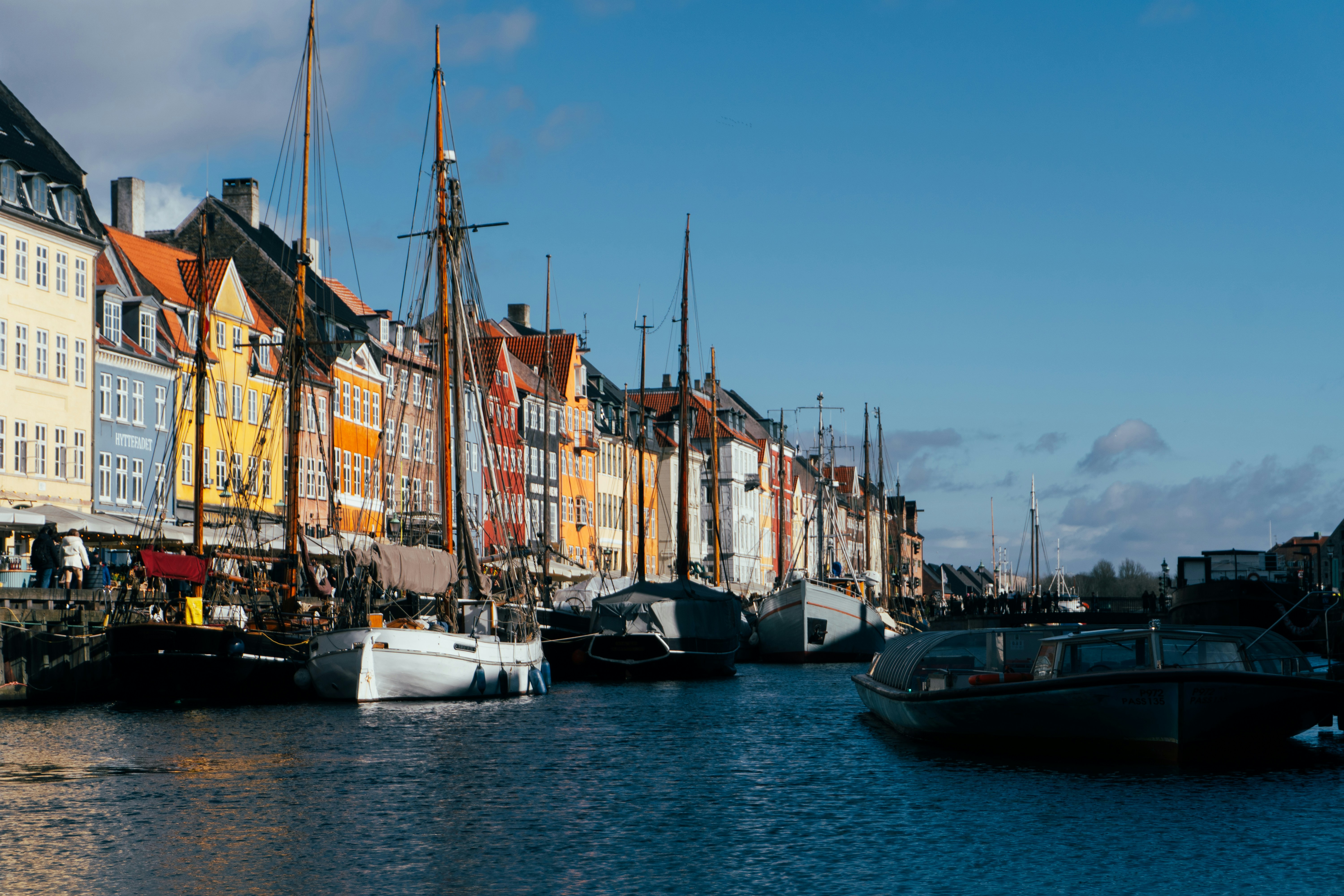 Colorful buildings lining a waterfront with boats anchored under a clear blue sky.