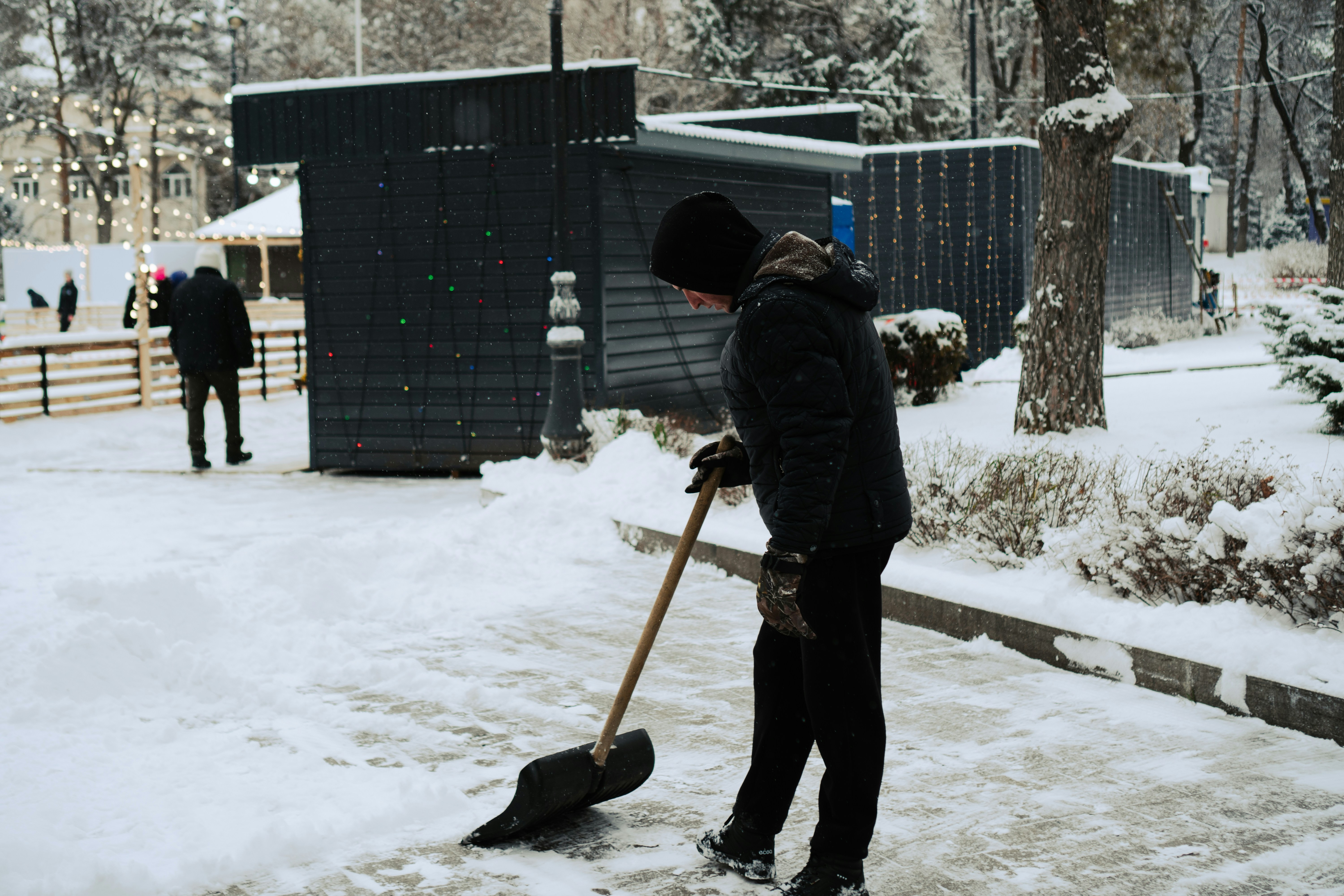 Snowbound Pause: A Worker Shoveling in a Quiet Park