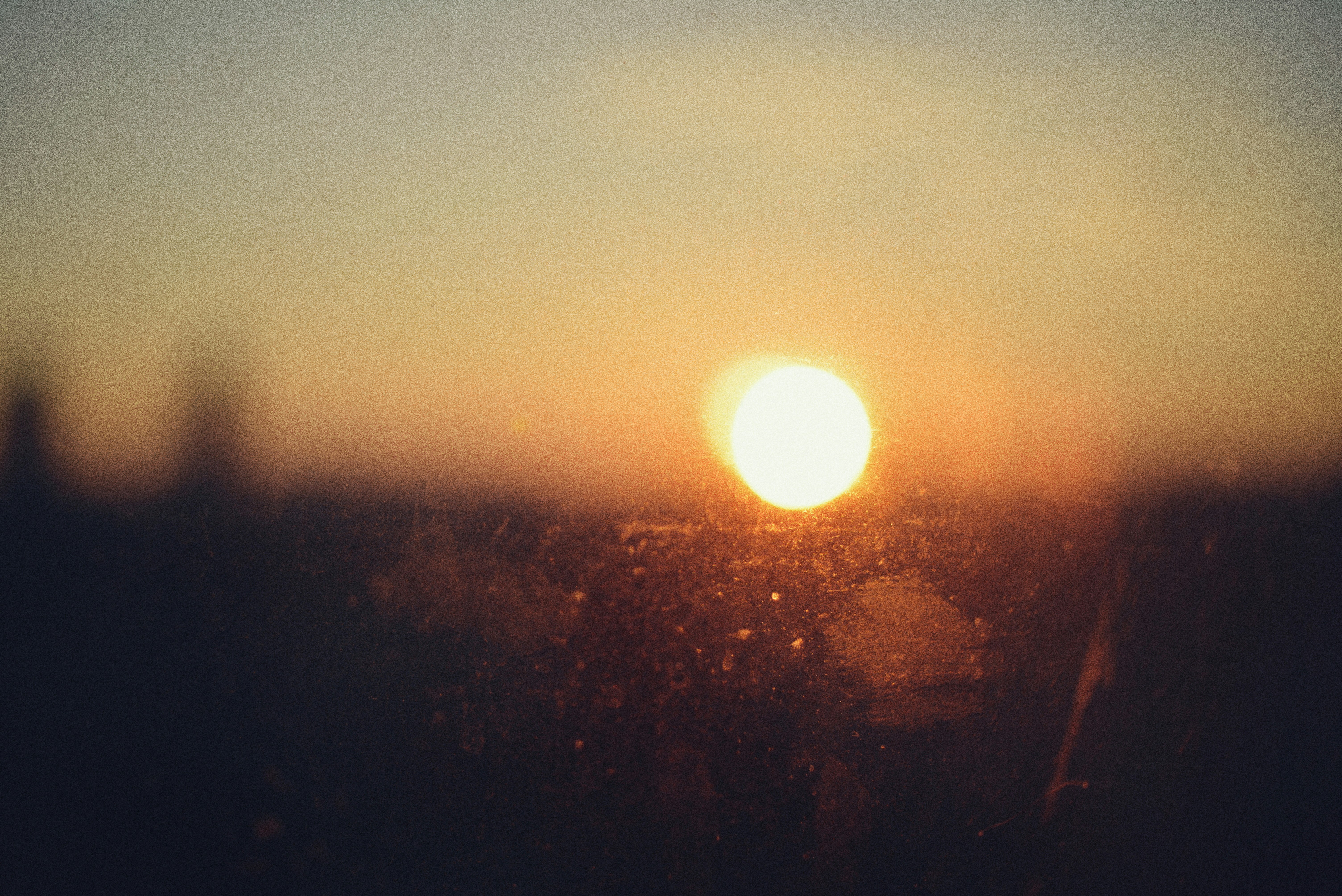 The golden sun sets over a dark horizon.