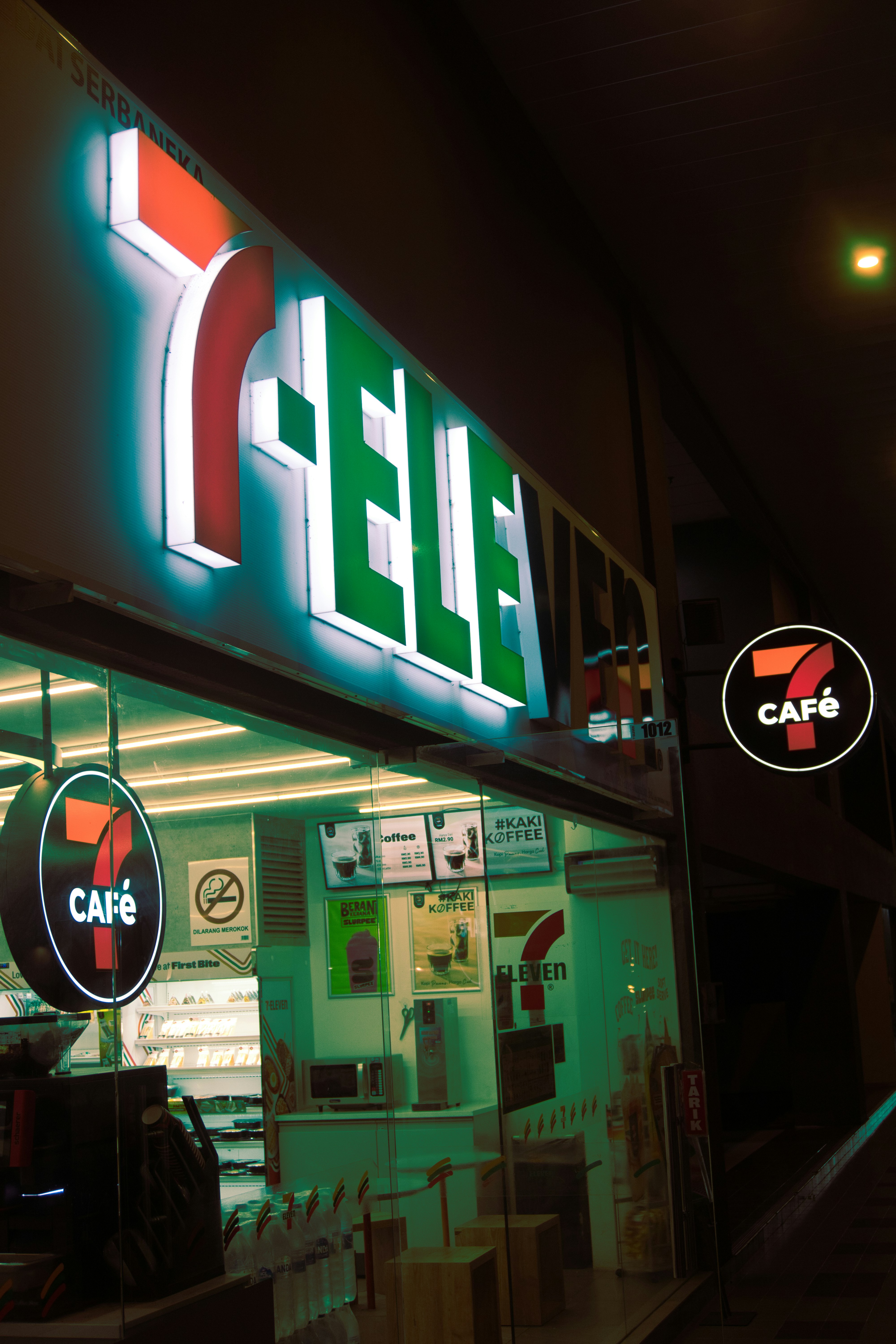 Neon 7-Eleven Glow Over a Glass-Walled Café