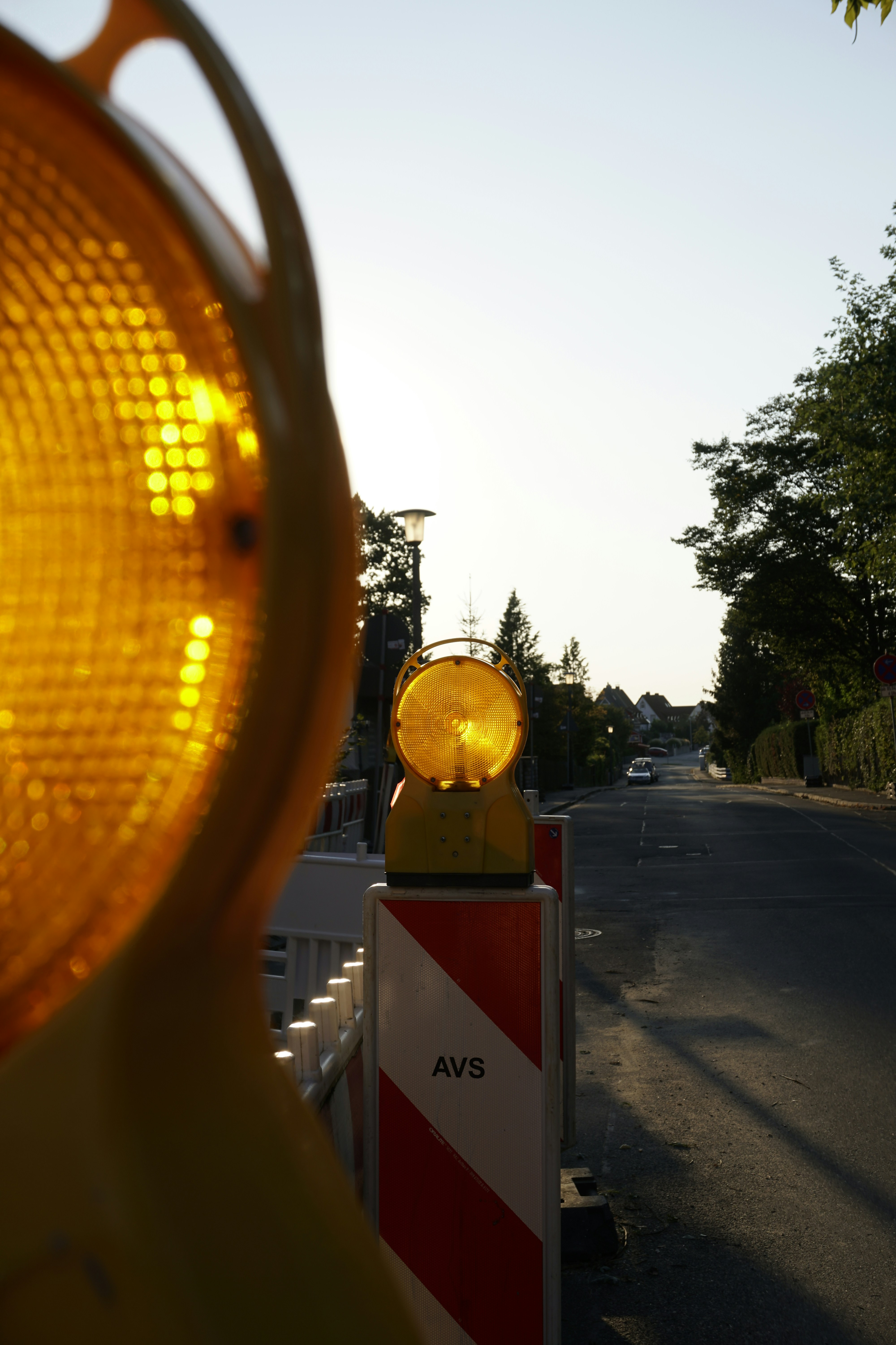 Dawn-Lit Barricade: Amber Safety Lights Guard a Quiet Suburban Street