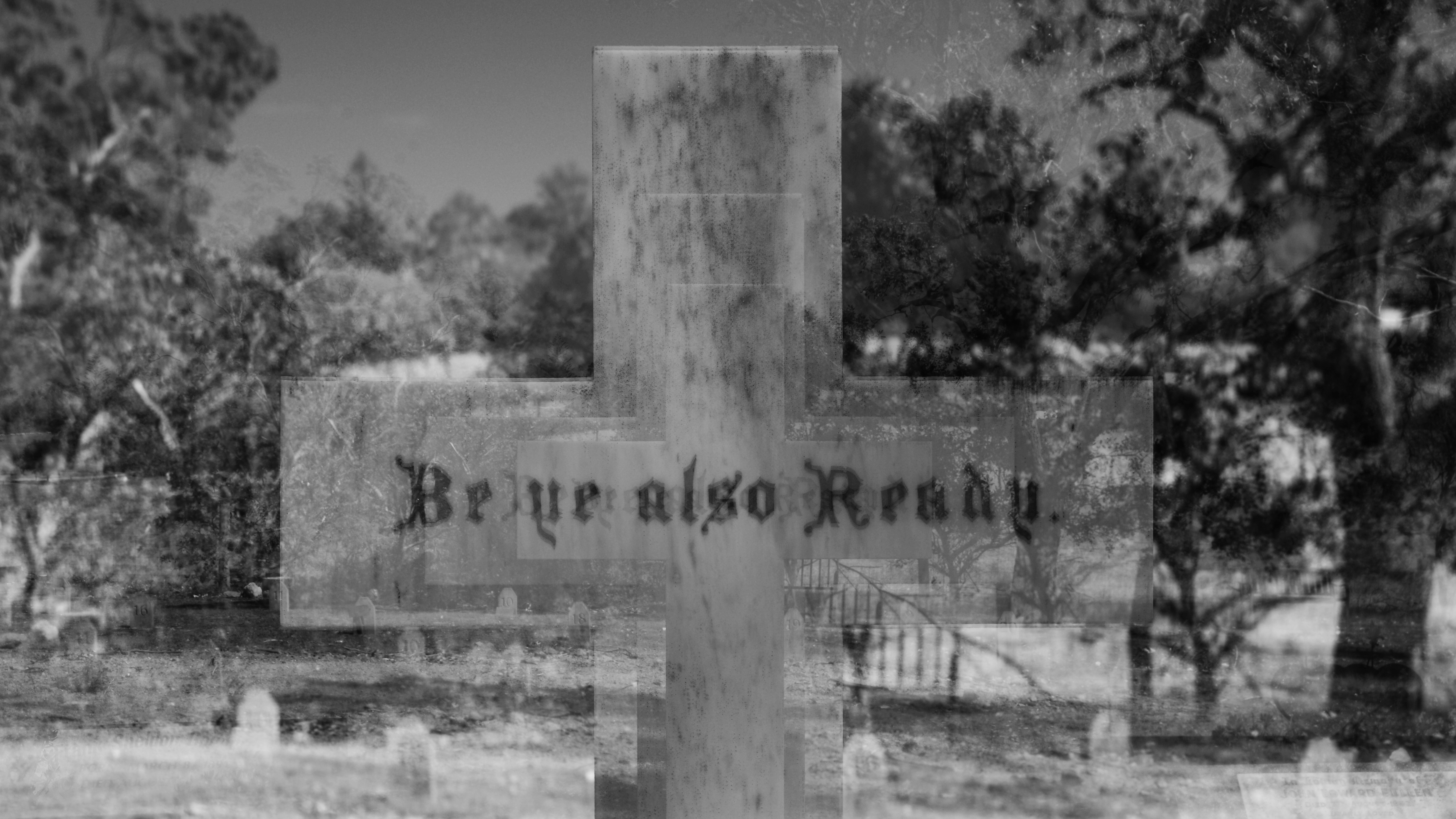 Weathered gravestone inscribed with 'Be ye also ready' in a serene cemetery setting, surrounded by trees.