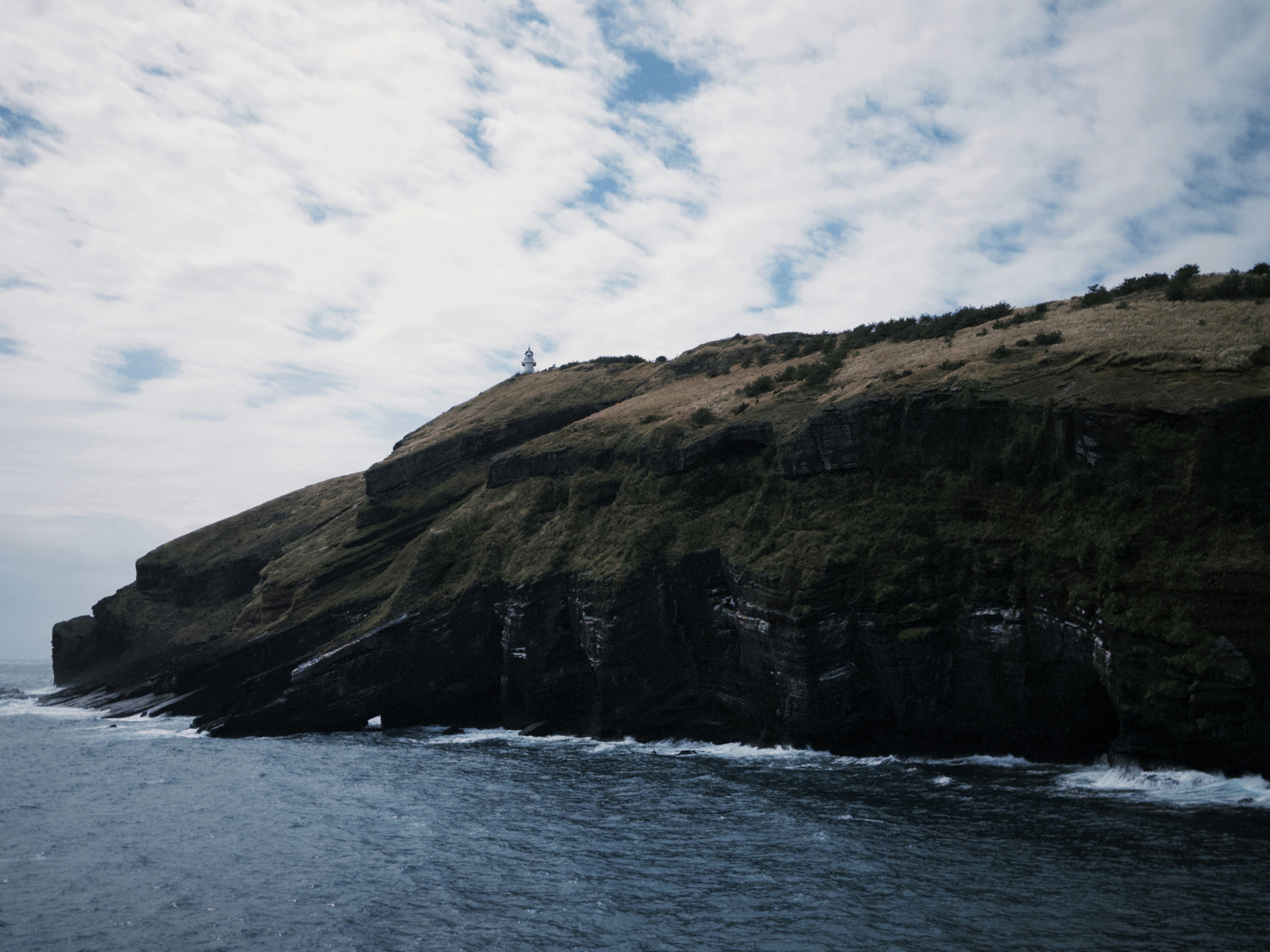 Cliffside with vegetation meets the sea. photo – Free Beach Image on ...