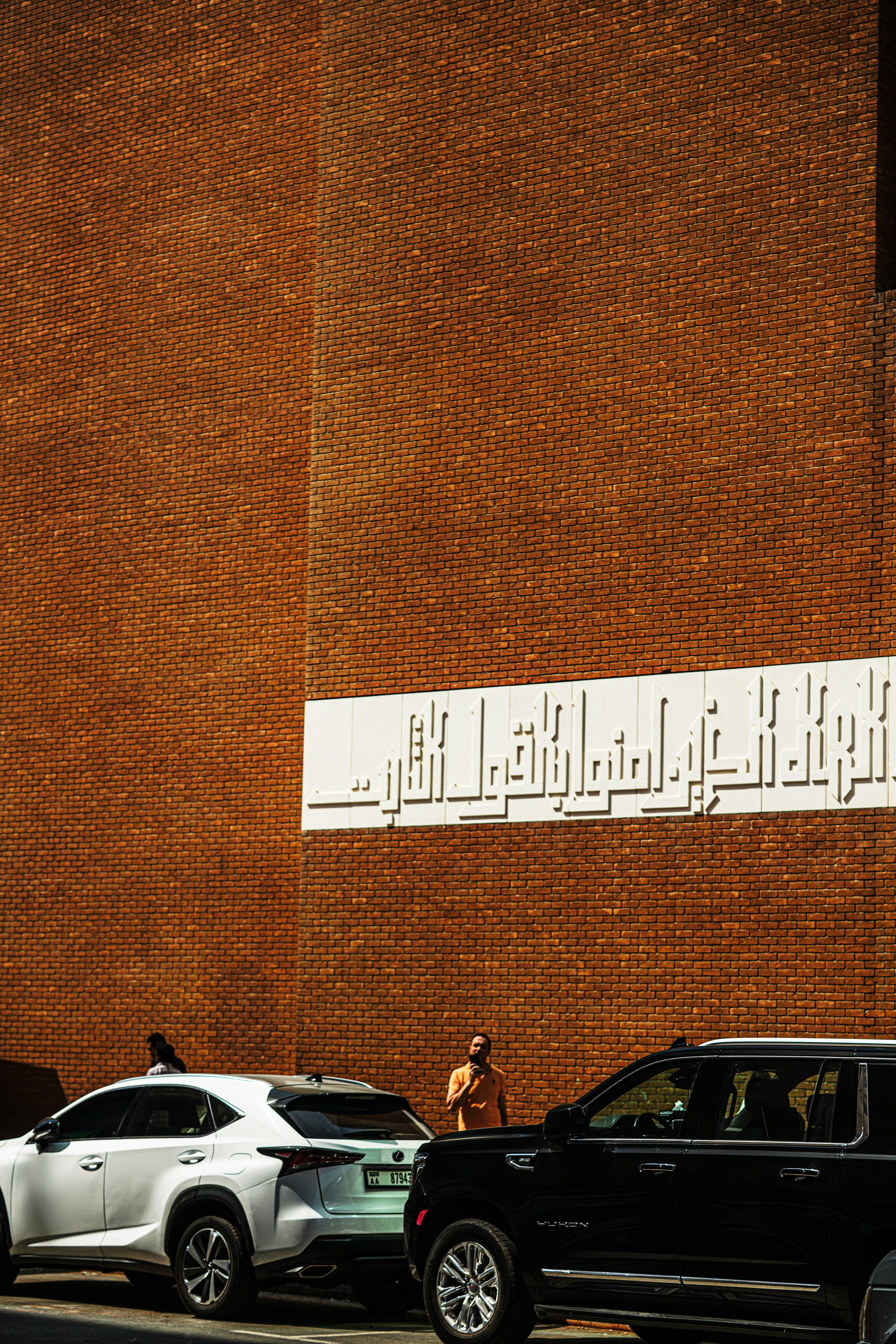 Cars are parked in front of a brick building.