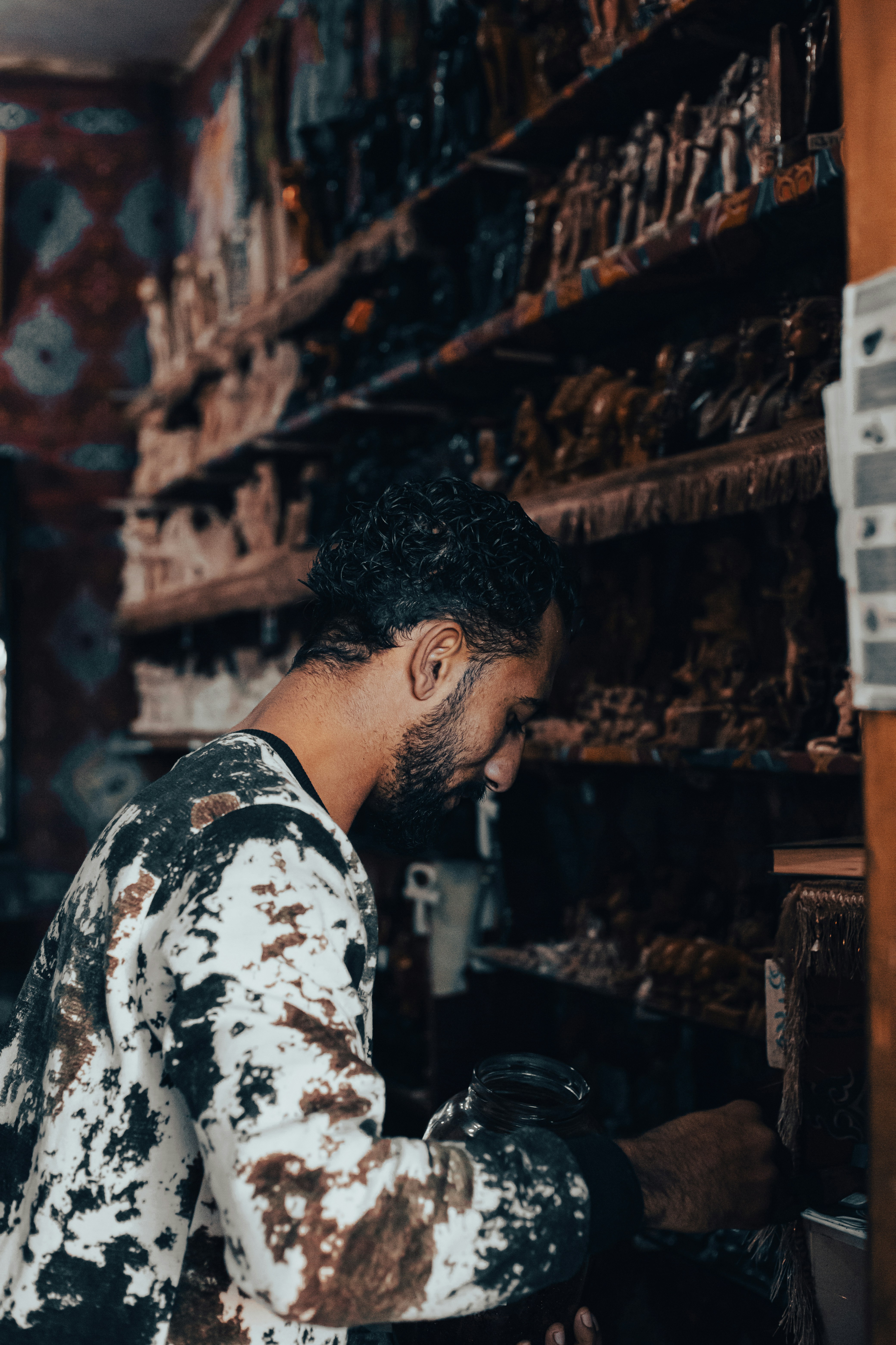 Paint-Splashed Quiet: A Craftsman in a Dim Shelf-Lined Workshop