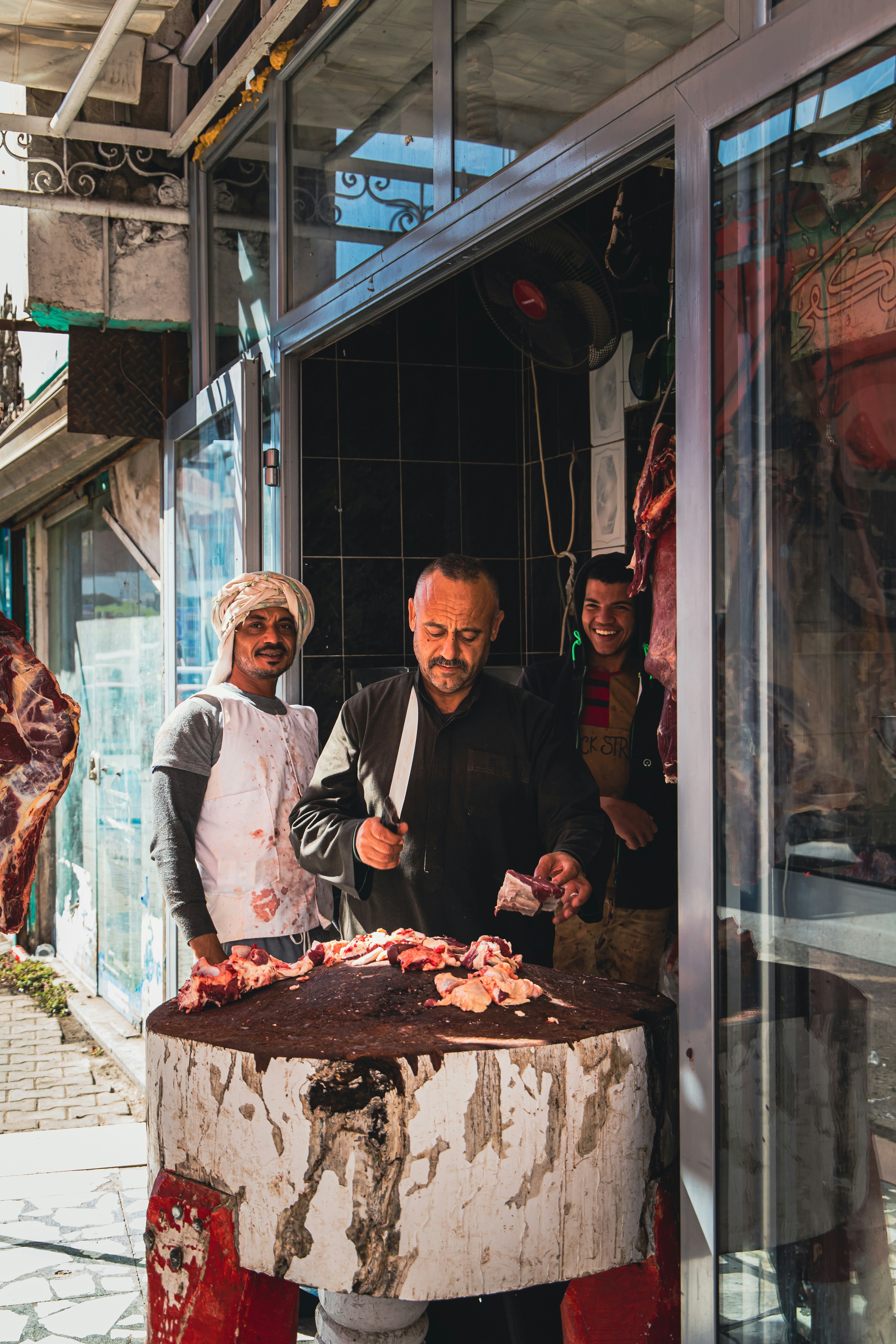 Butcher cuts meat behind the counter of a shop. photo – Free Portrait ...