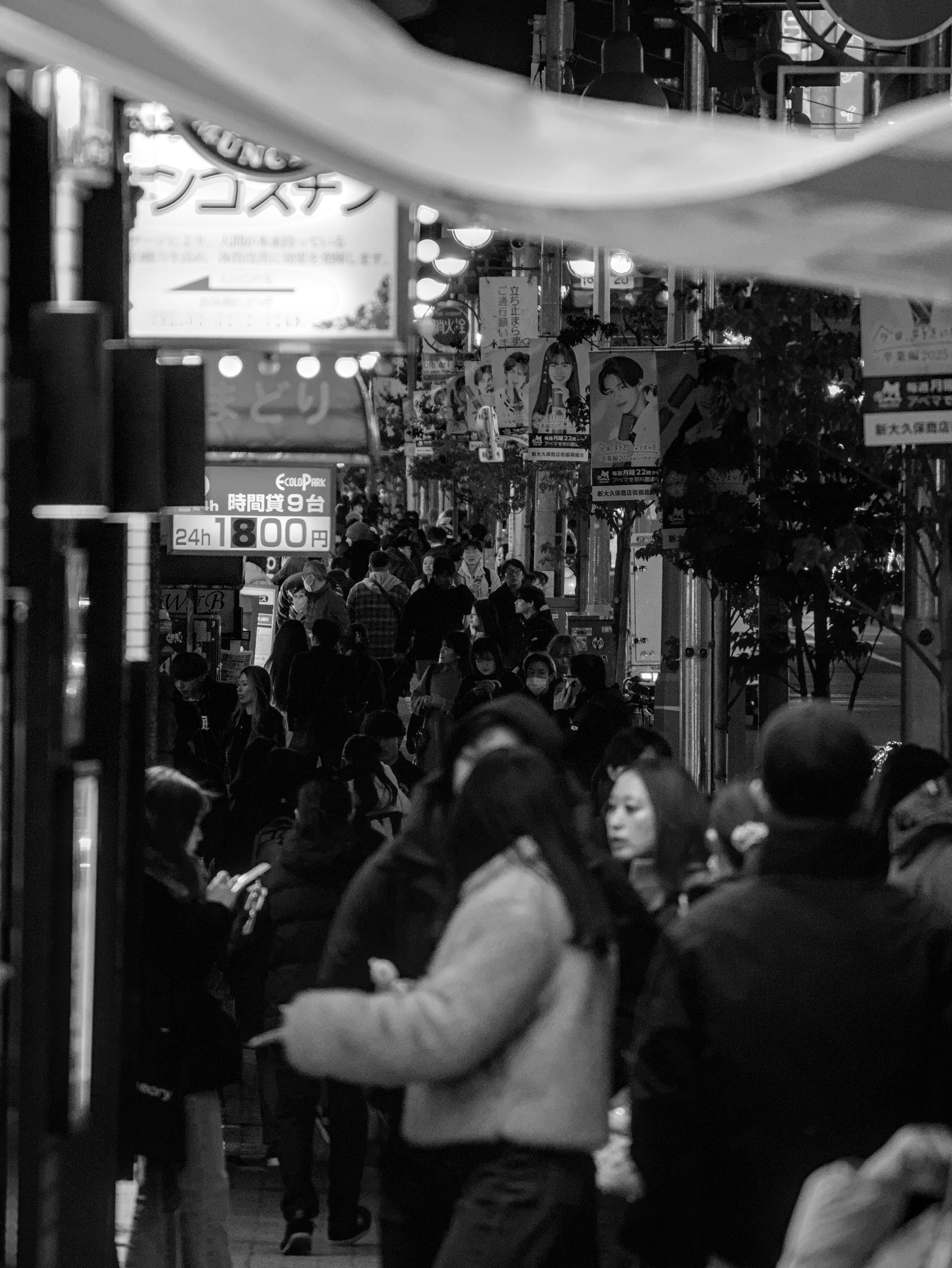 Monochrome Junction: Crowded Signs and Faces on a Night Street