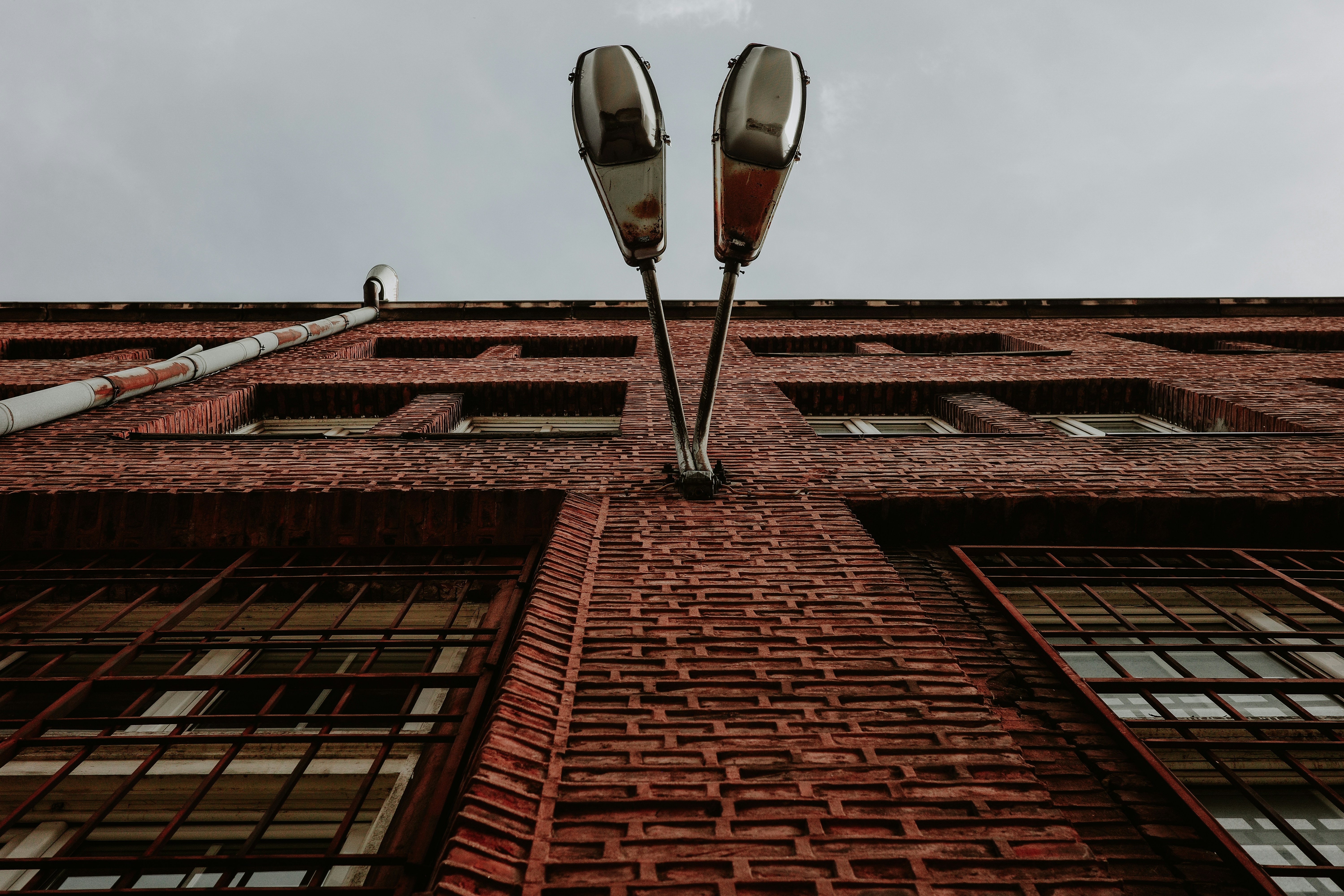 The image shows streetlights on a brick building. photo – Free Building ...