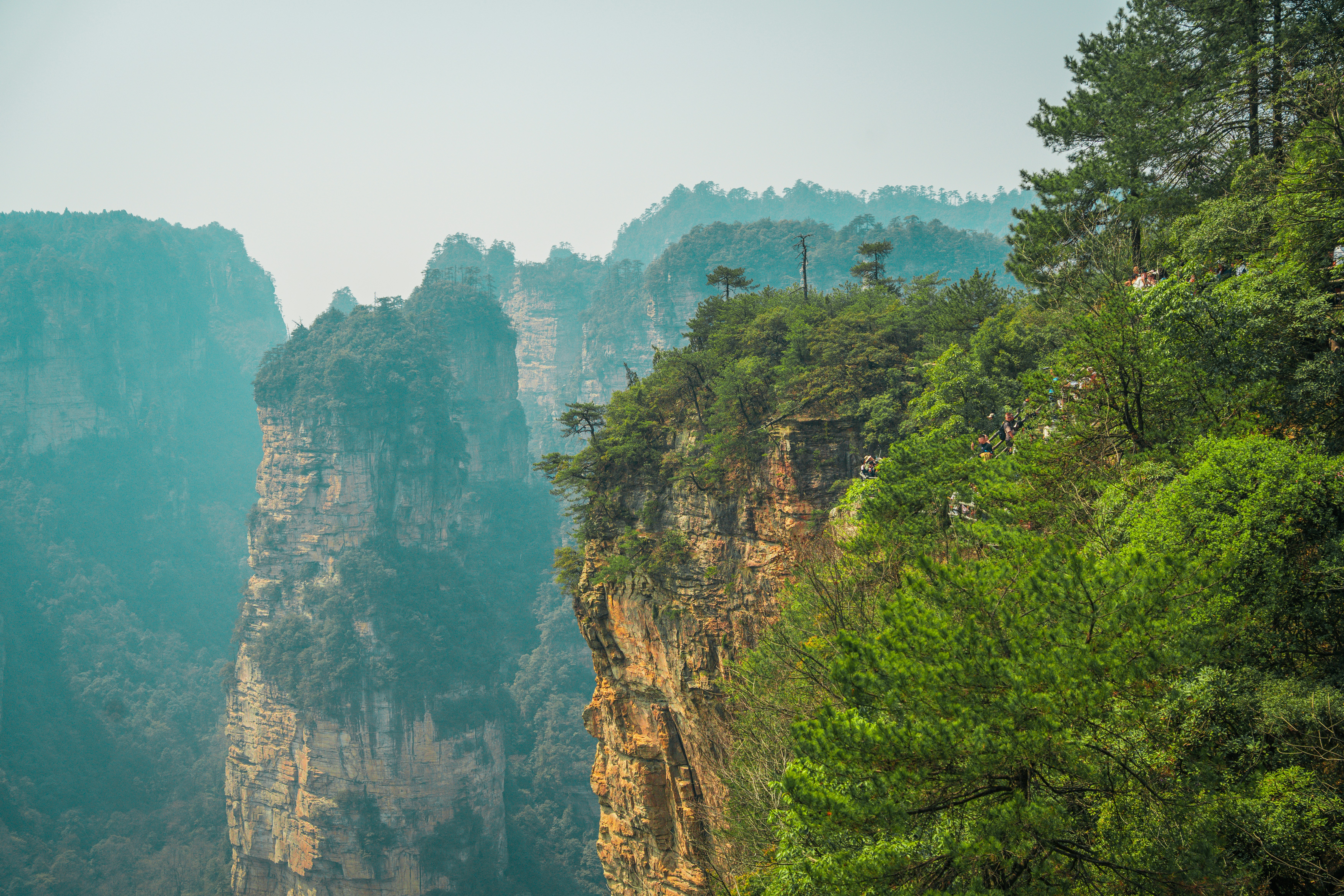 Towering rock formations stand amidst lush green trees. photo – Free ...