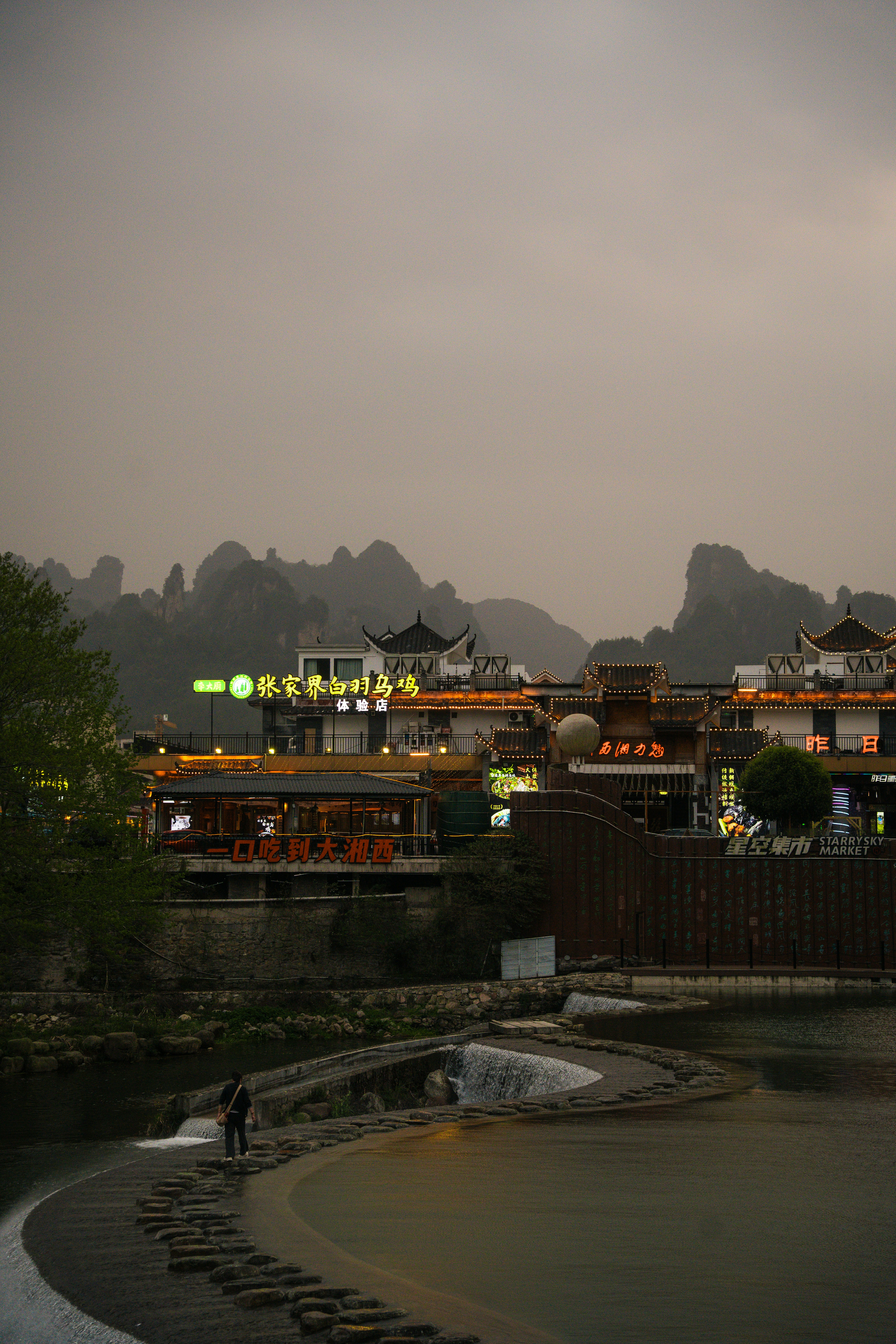 Neon Riverside at Dusk: Lantern-lit Borough Beneath Karst Peaks