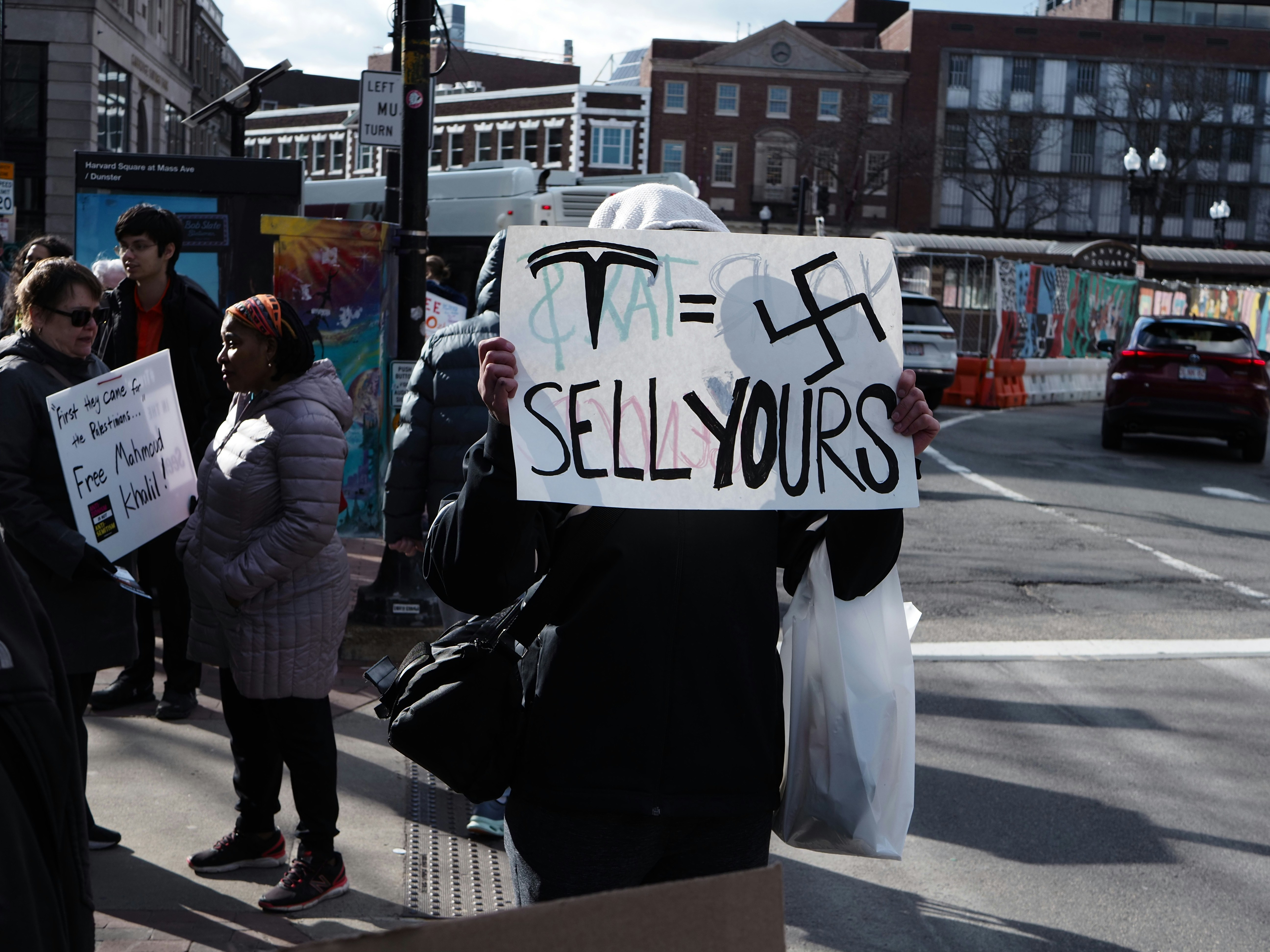 Protester equates tesla logo with a swastika, saying sell yours. photo ...
