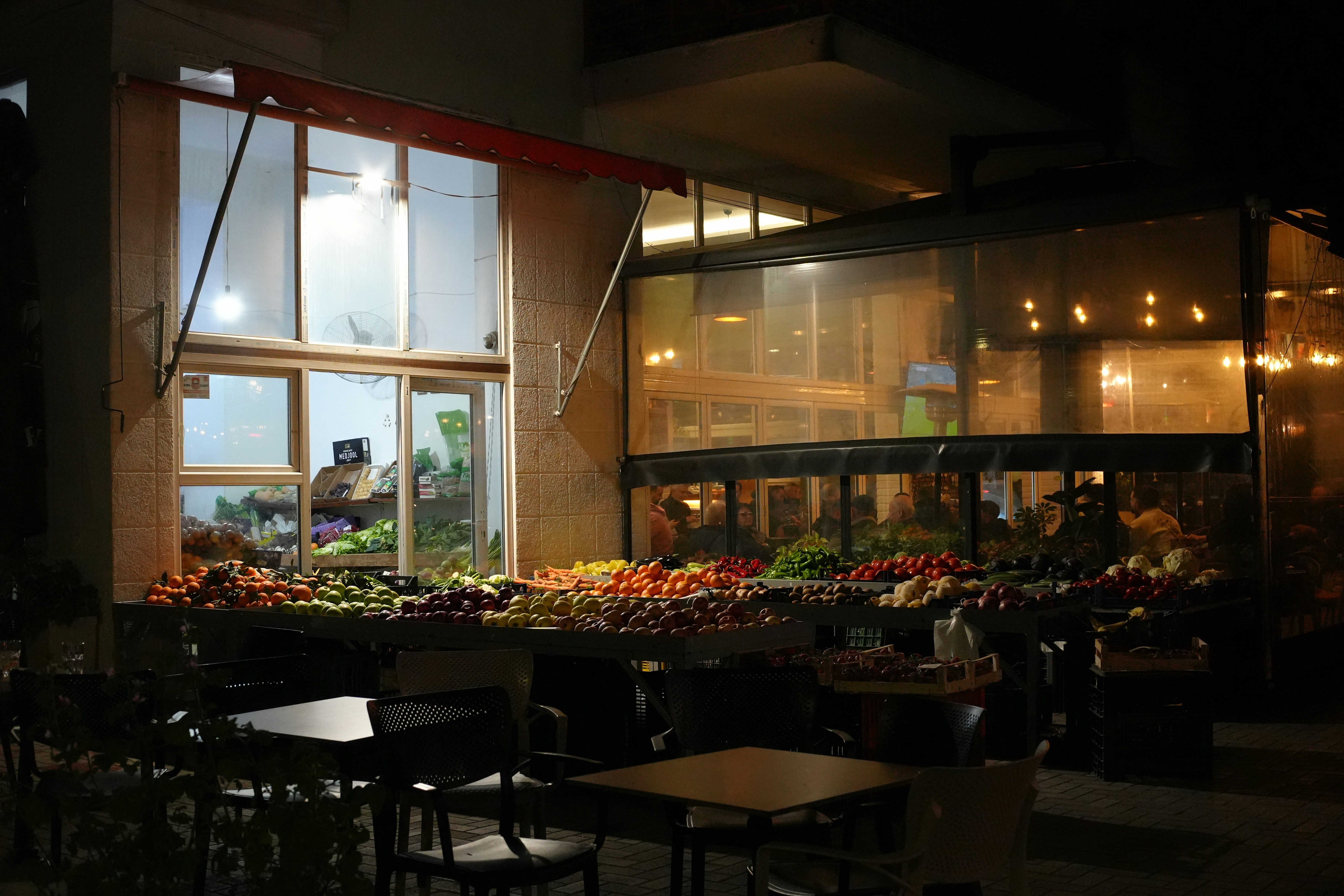 A well-lit shop displays fruits and vegetables at night. photo – Free ...