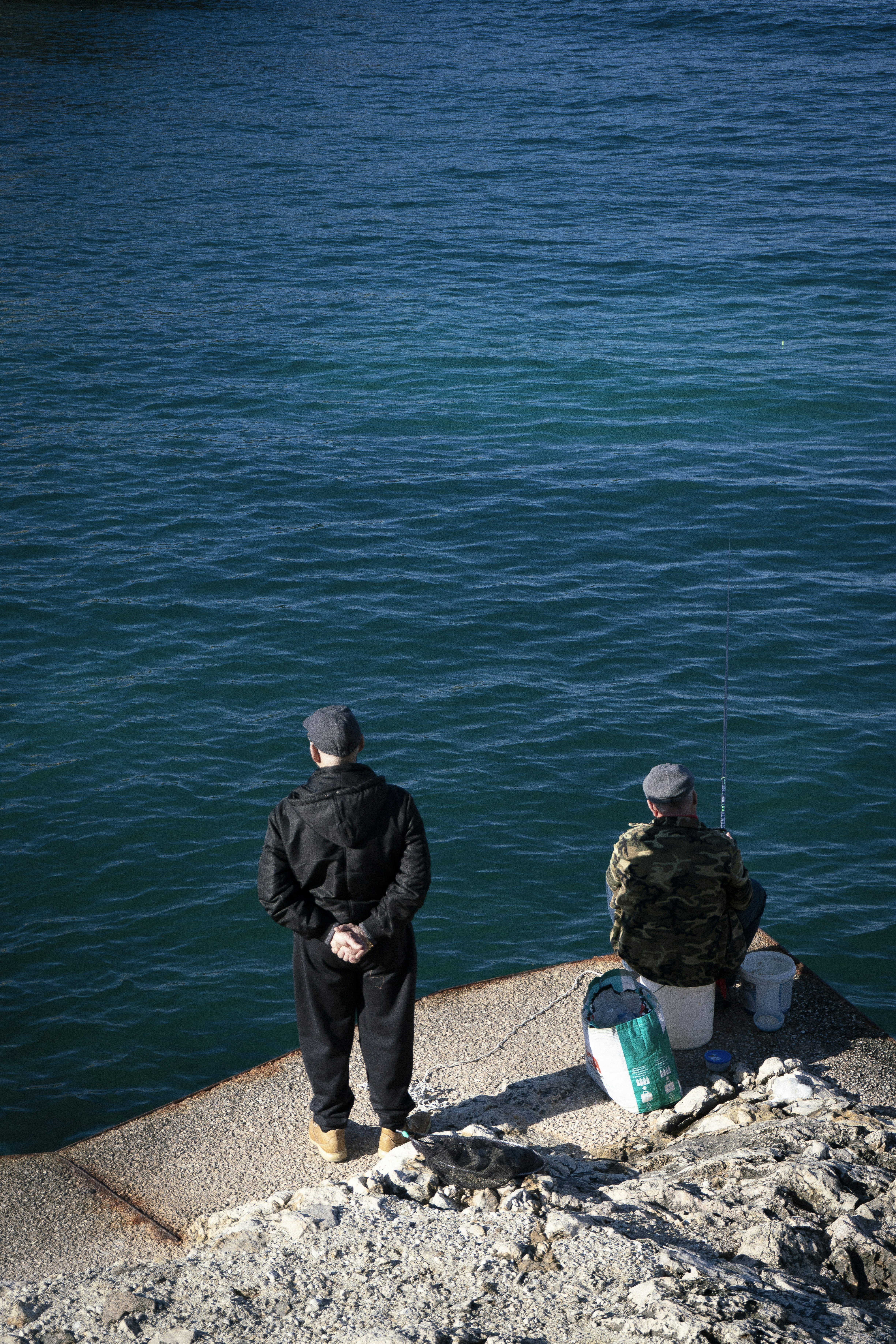 Pierside Quiet: A Pair of Anglers Against a Sapphire Sea